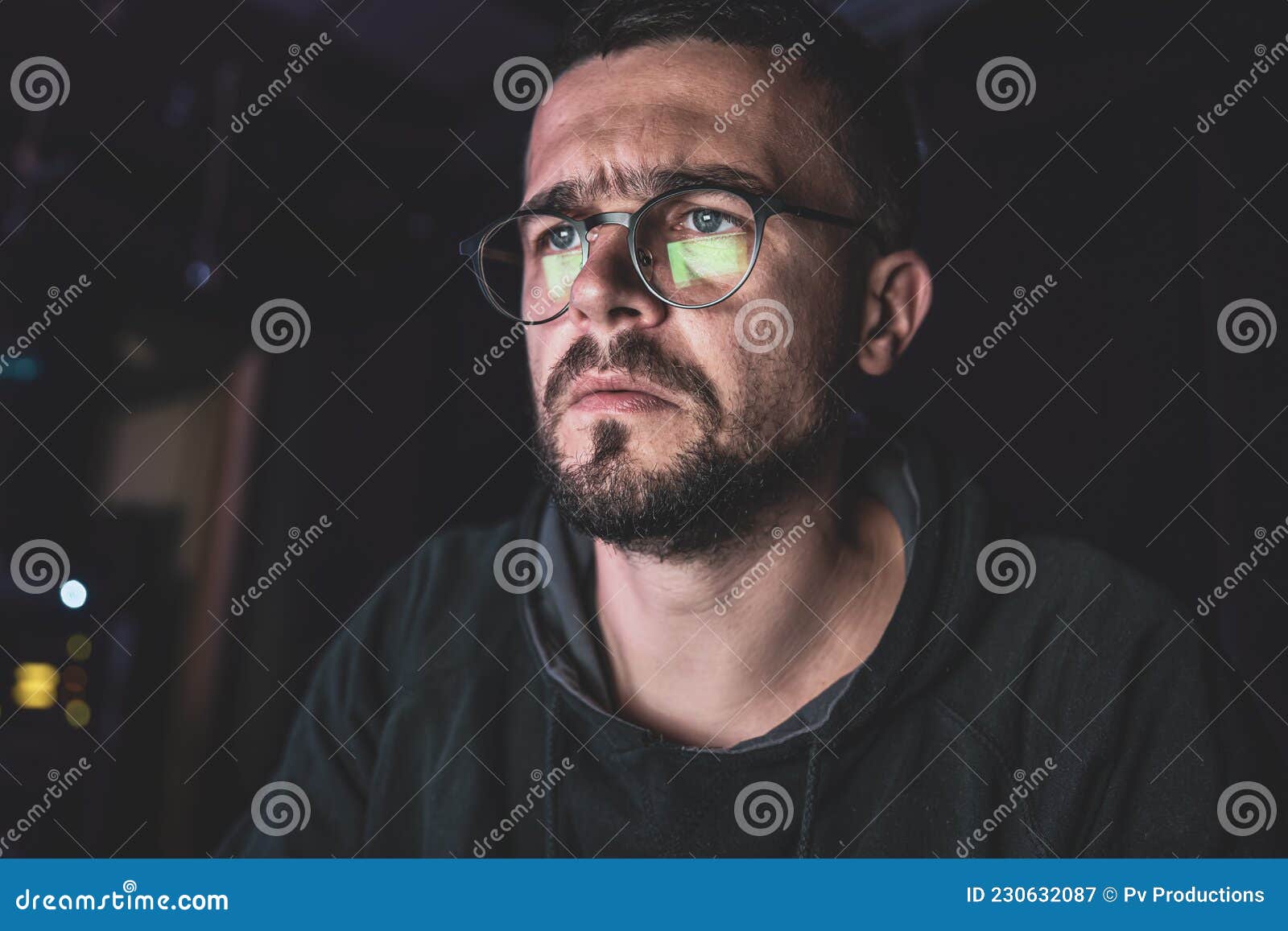 A Man Wearing Glasses Stares Intently at a Computer Screen Late at ...