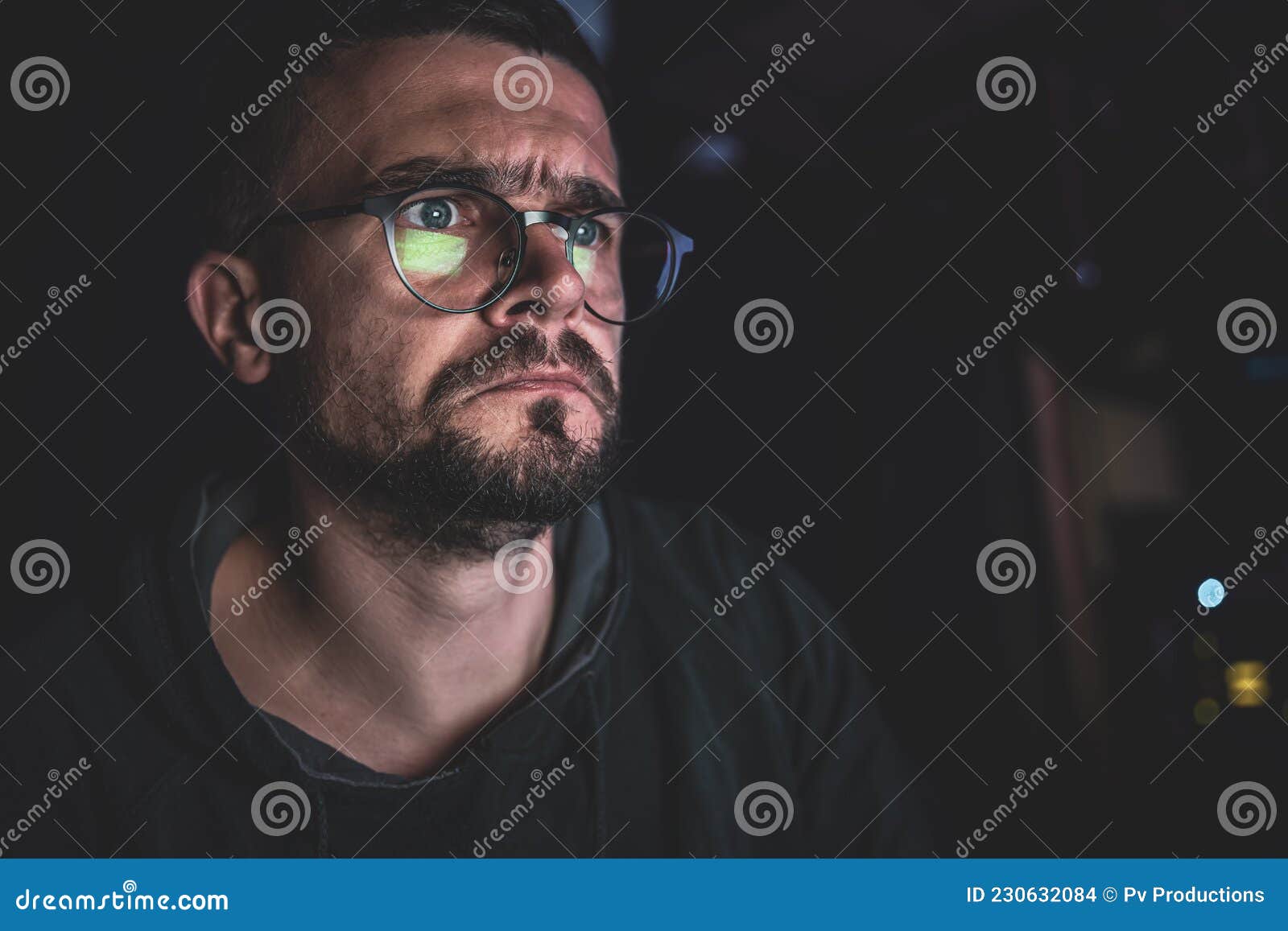 A Man Wearing Glasses Stares Intently at a Computer Screen Late at ...