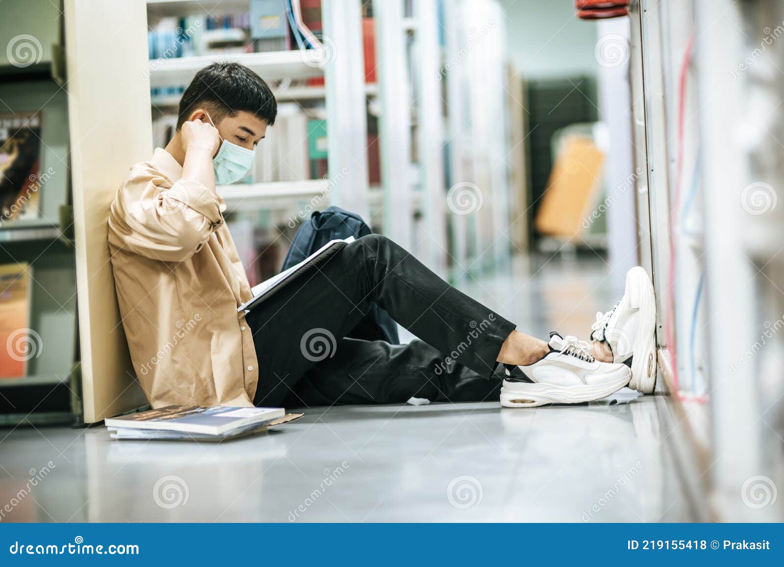 A Man Wearing Masks is Sitting Reading a Book in the Library Stock ...