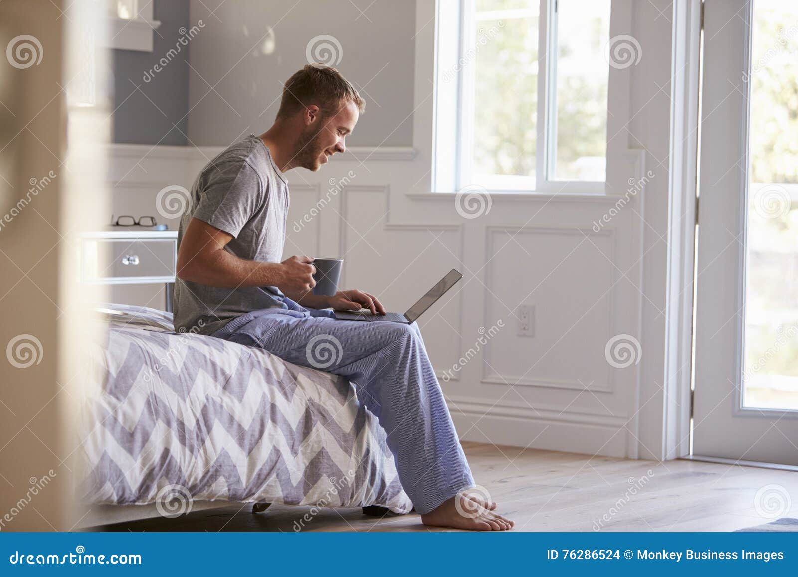 Man Wearing Pajamas Using Laptop Computer in Bedroom Stock Photo ...