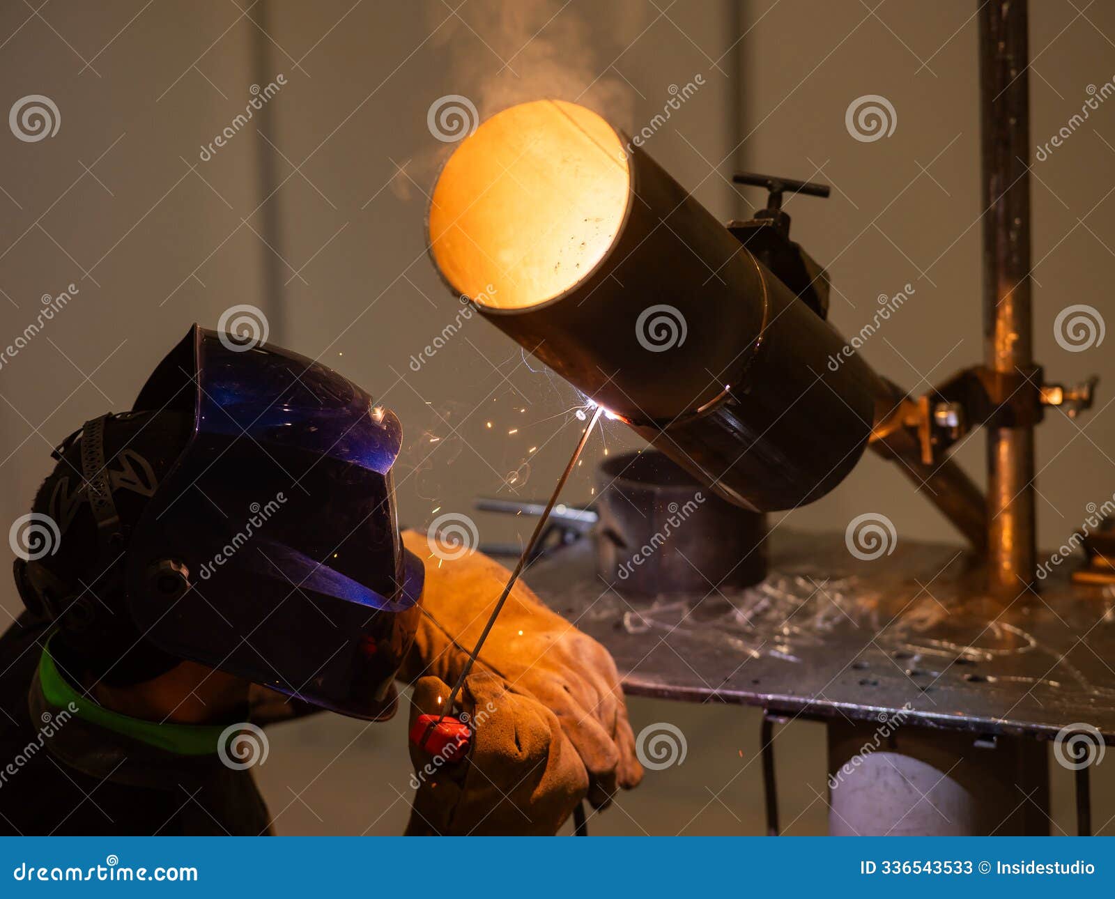 A Man Wearing a Protective Mask Welds a Metal Pipe. Stock Image - Image ...