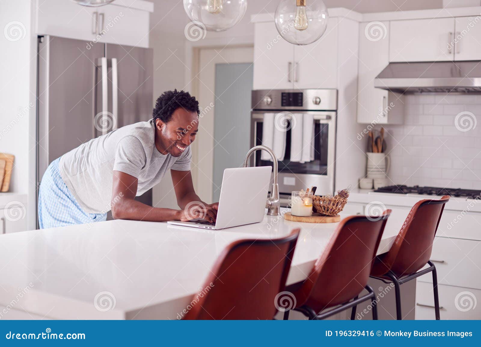 Man Wearing Pyjamas Standing in Kitchen Working from Home on Laptop ...