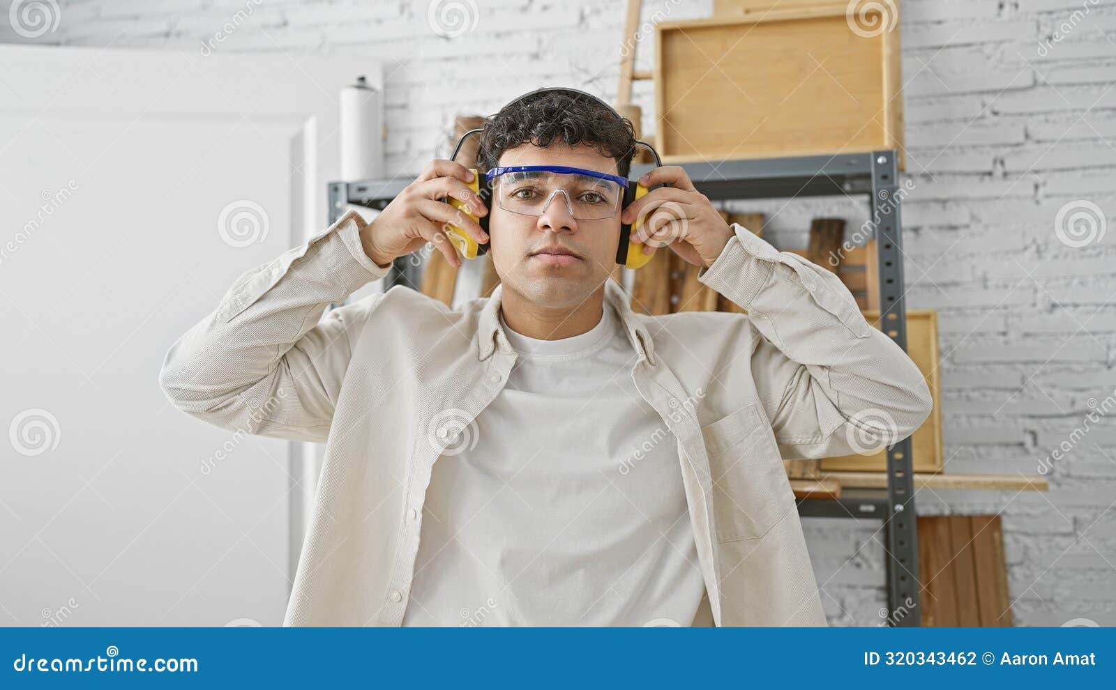 A Man Wearing Safety Goggles and Ear Protection in a Bright Carpentry ...