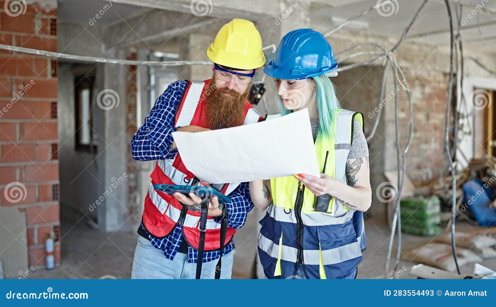 Man and Woman Builders Using Touchpad Reading House Project at ...