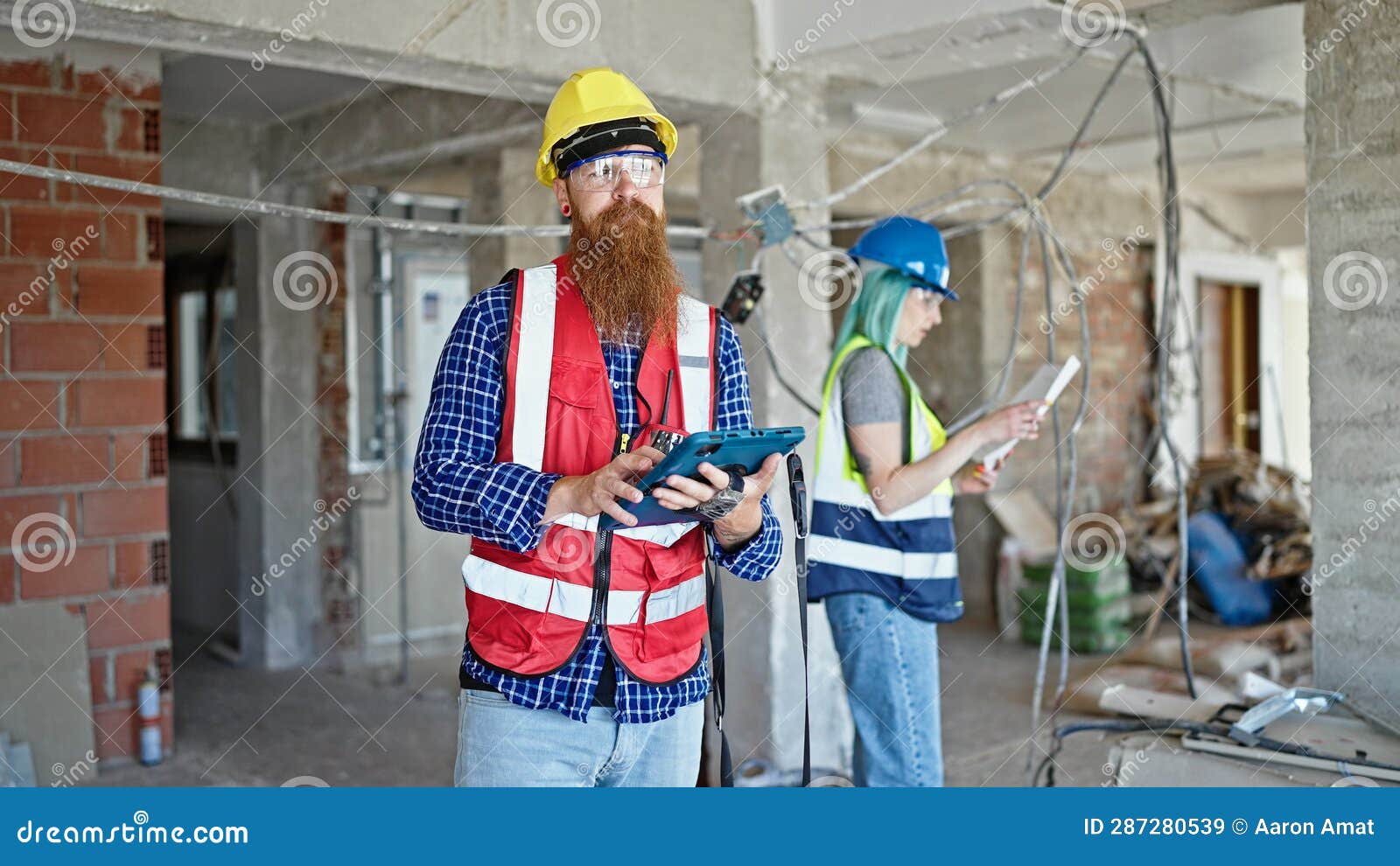 Man and Woman Builders Using Touchpad Reading House Project at ...