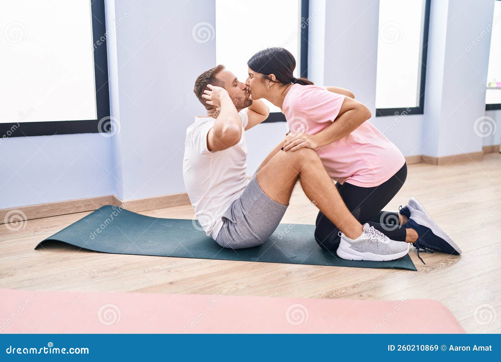 Man And Woman Couple Training Abs Exercise And Kissing At Sport Center