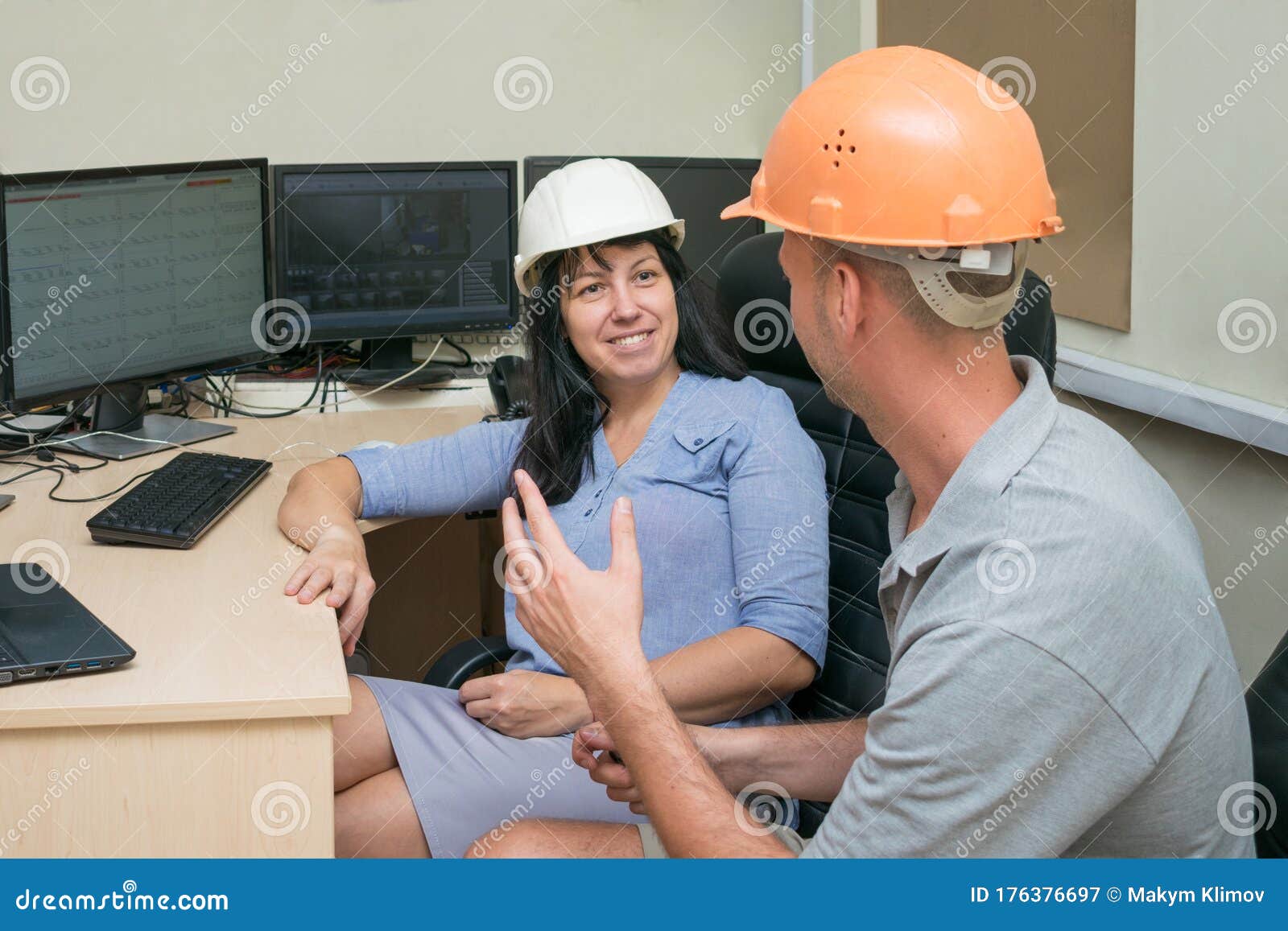 A Man and a Woman in Engineering Helmets are Talking in Front of the ...