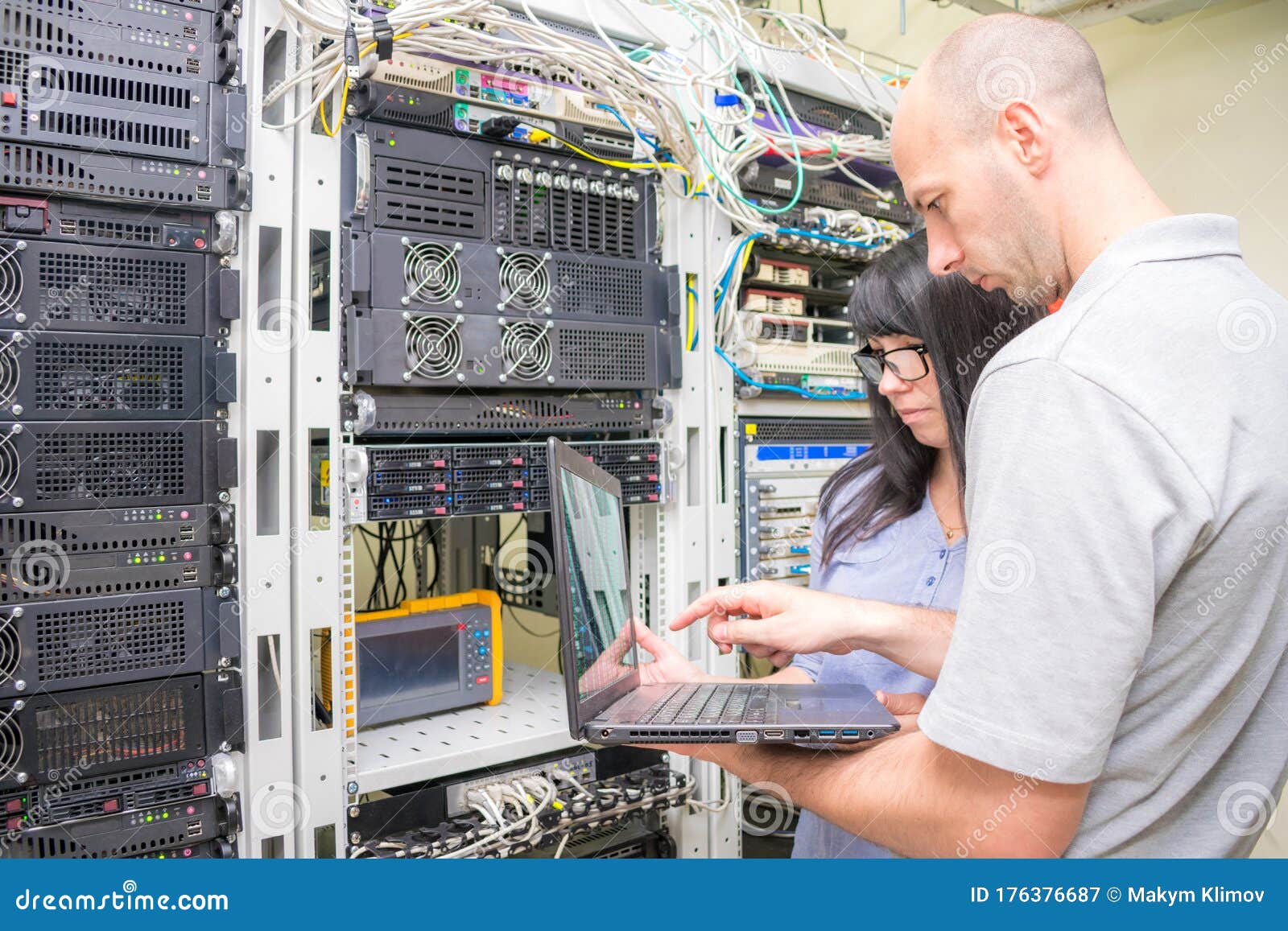 A Man and a Woman with a Notebook Work in a Server Room. Experts Look ...