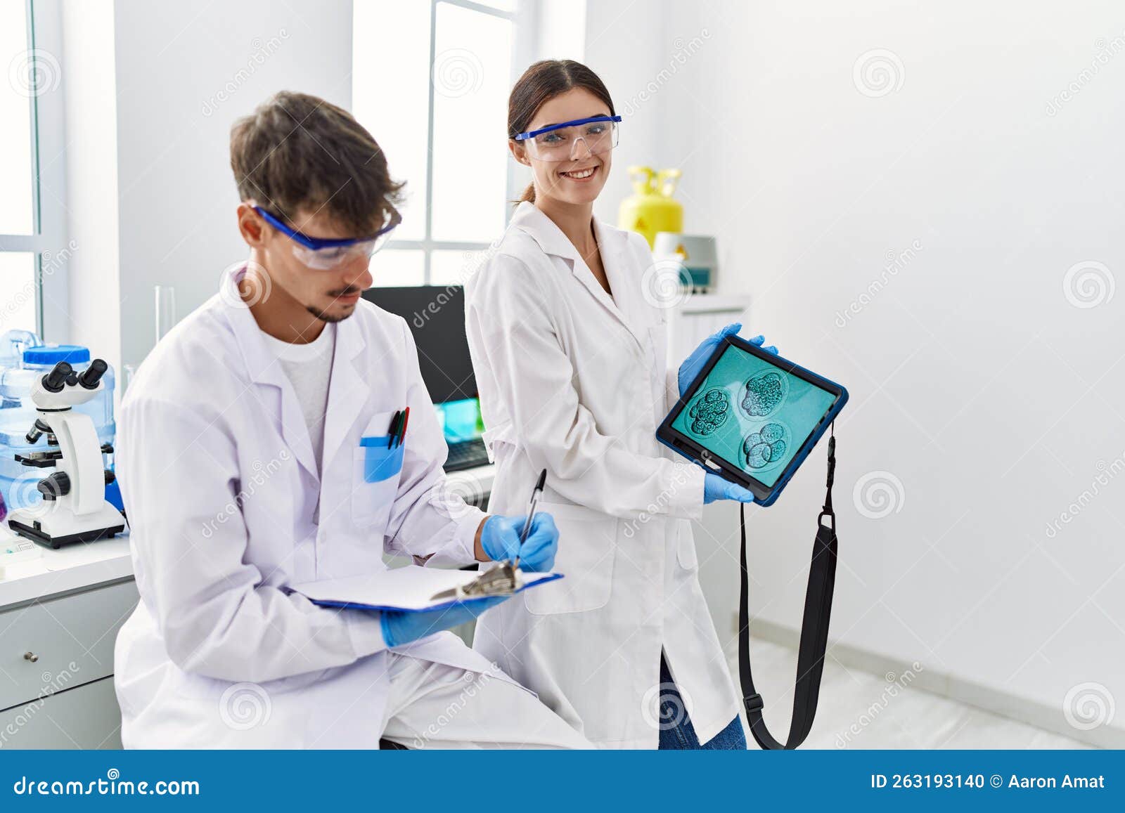 Man and Woman Partners Wearing Scientist Uniform Using Touchpad with ...