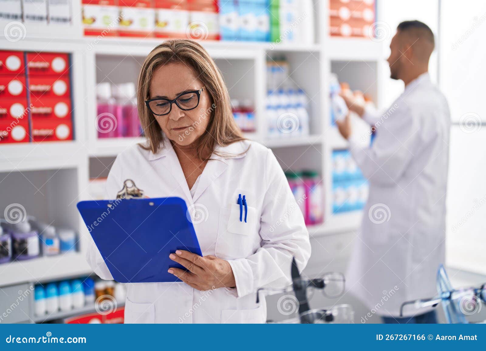 Man and Woman Pharmacist Writing on Document at Pharmacy Stock Photo ...