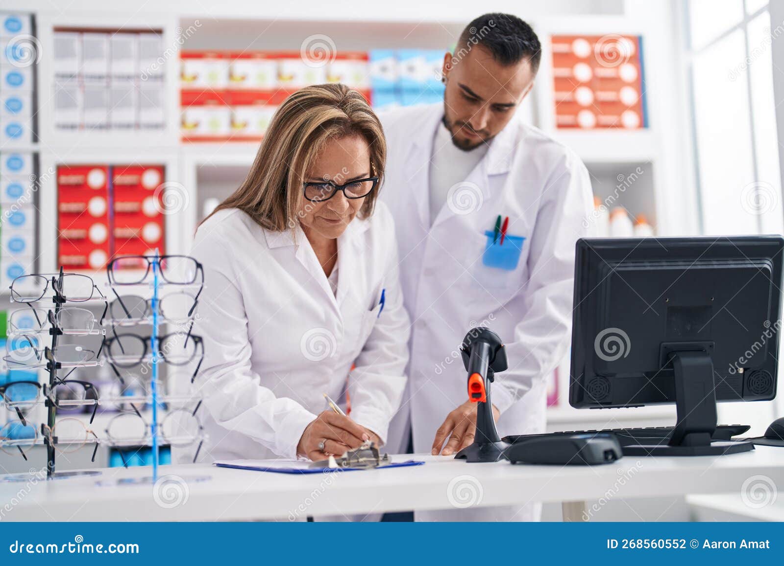 Man and Woman Pharmacist Writing on Document at Pharmacy Stock Photo ...