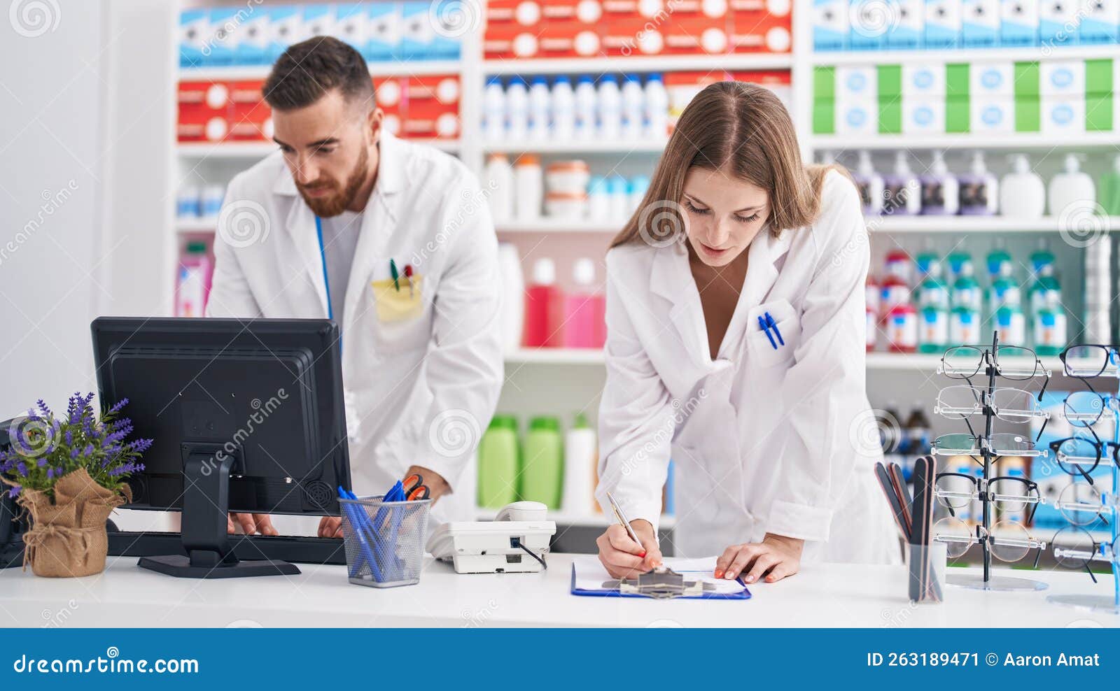 Man and Woman Pharmacists Using Computer Writing on Document at ...