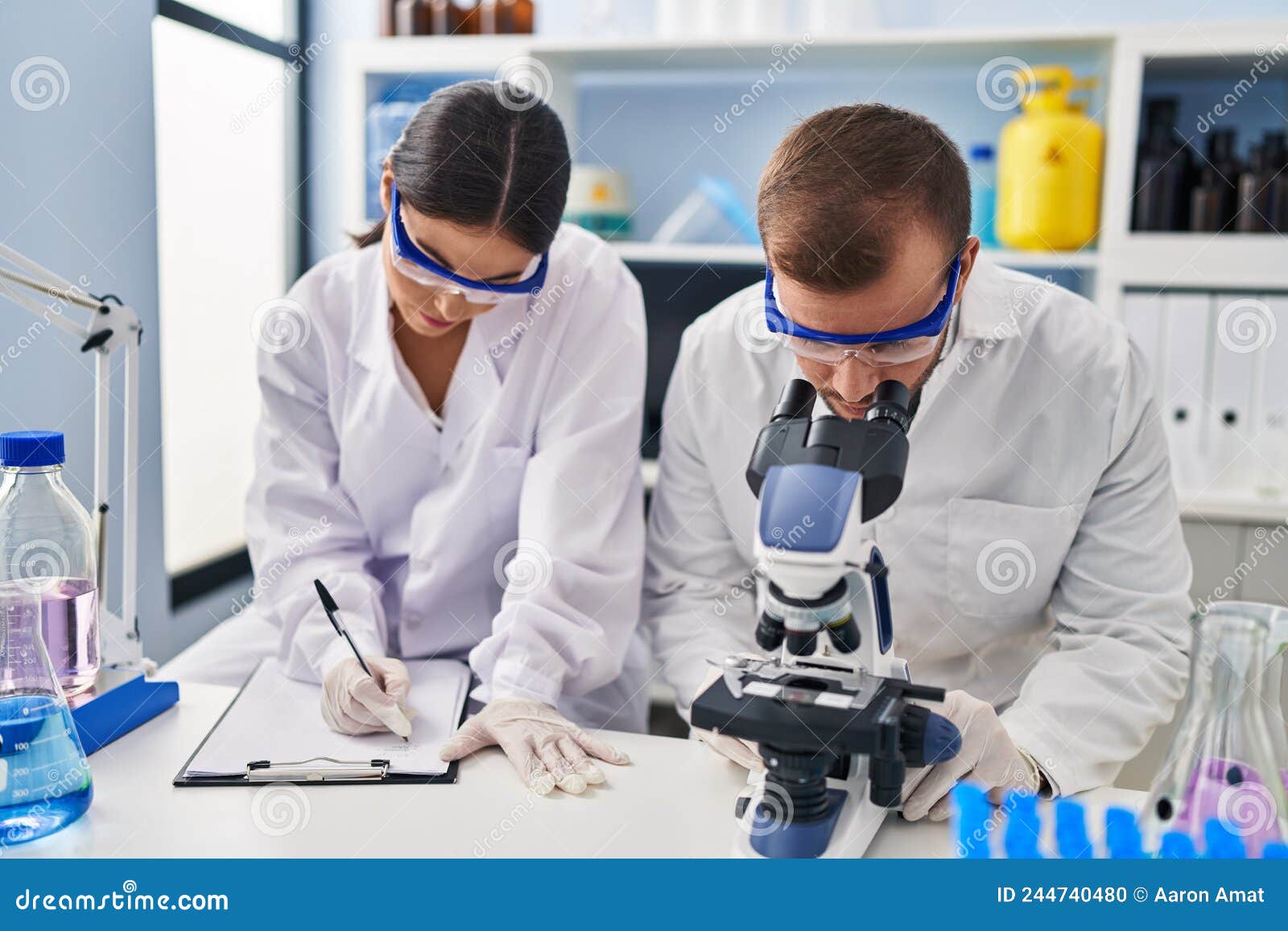 Man and Woman Scientist Partners Working Using Microscope and Writing ...