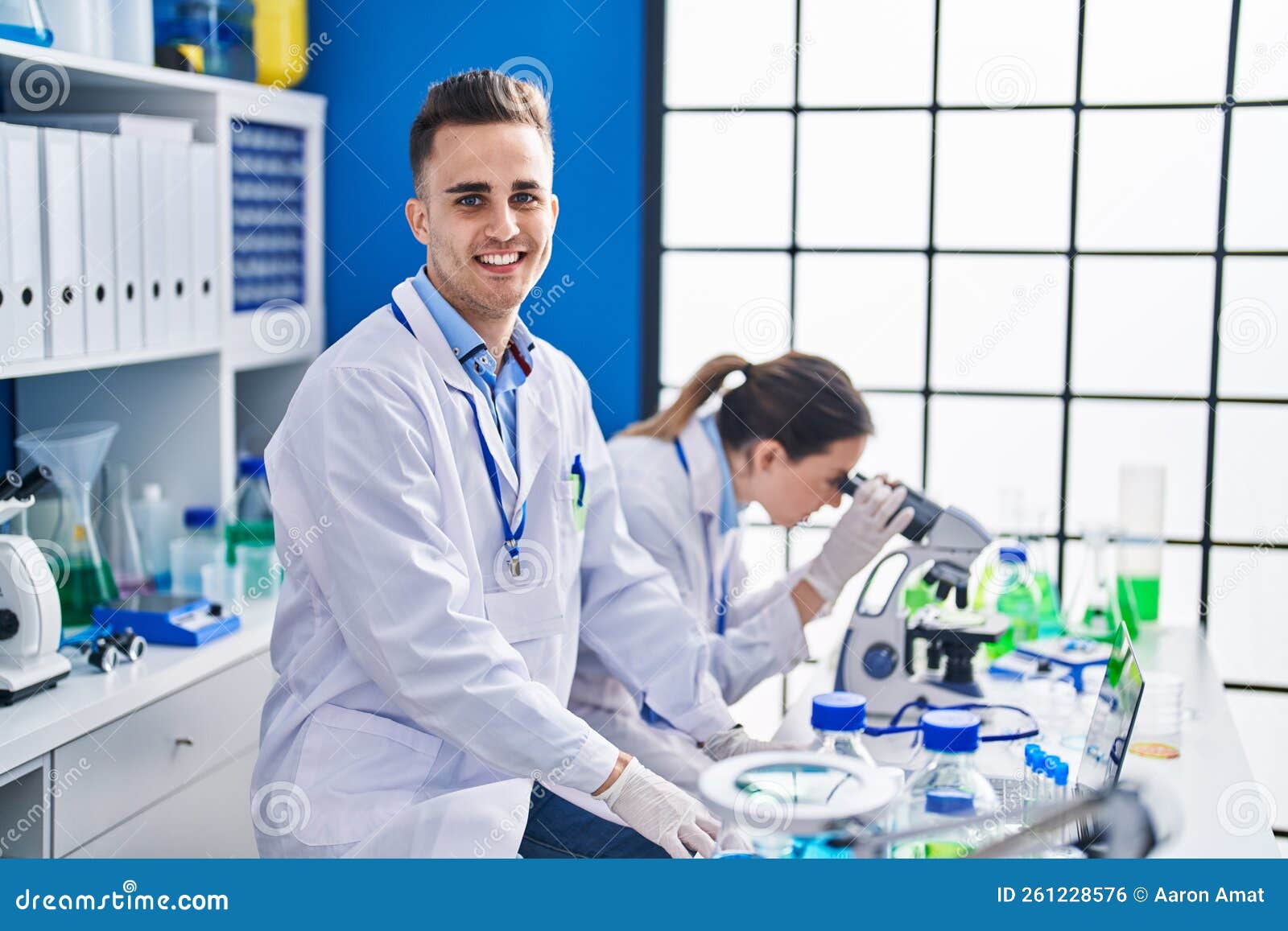 Man and Woman Scientists Using Laptop and Microscope at Laboratory ...