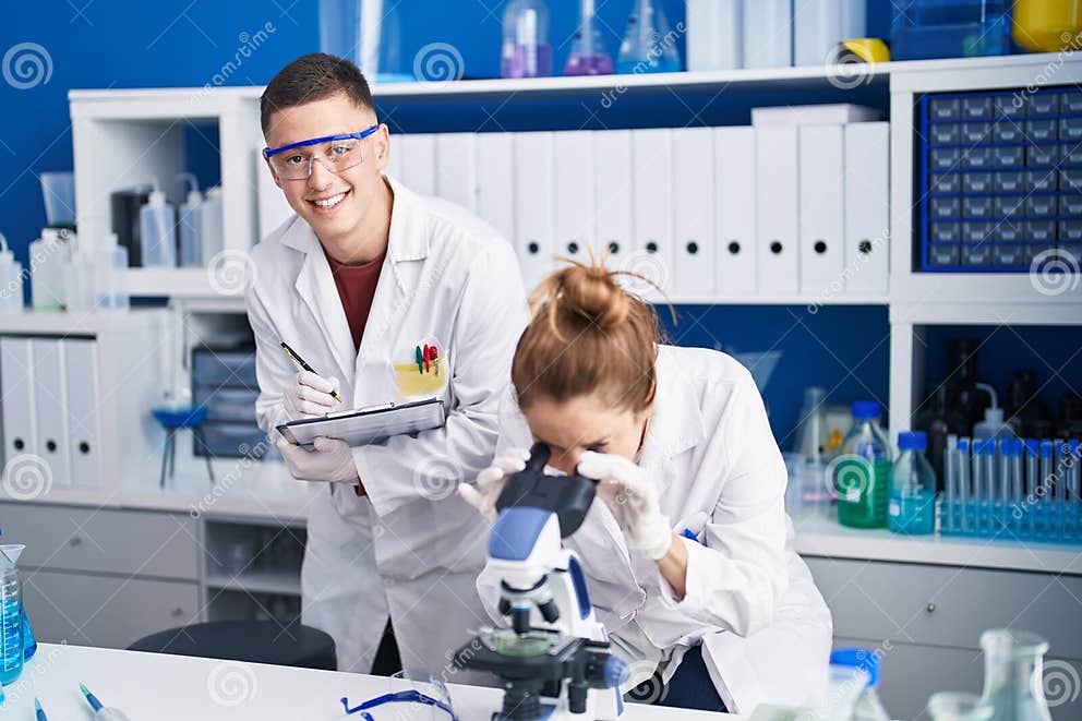 Man and Woman Scientists Using Microscope Write on Document at ...