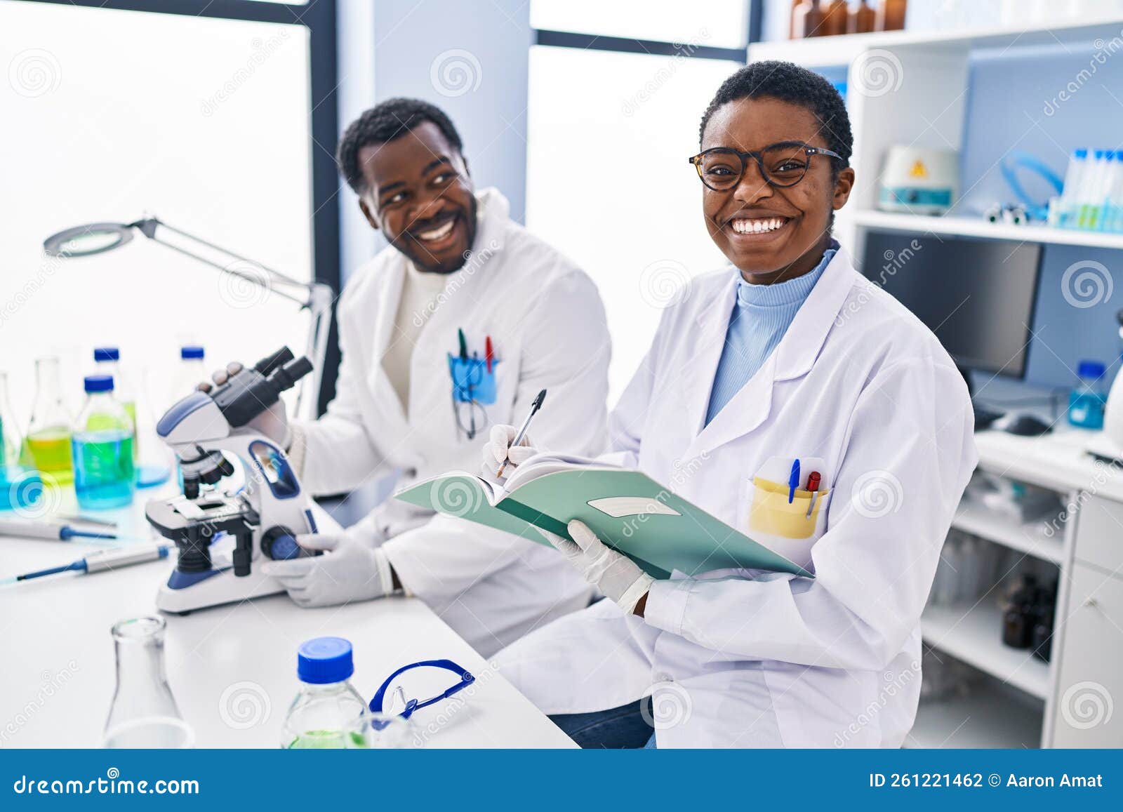 Man and Woman Scientists Using Microscope Writing on Notebook at ...
