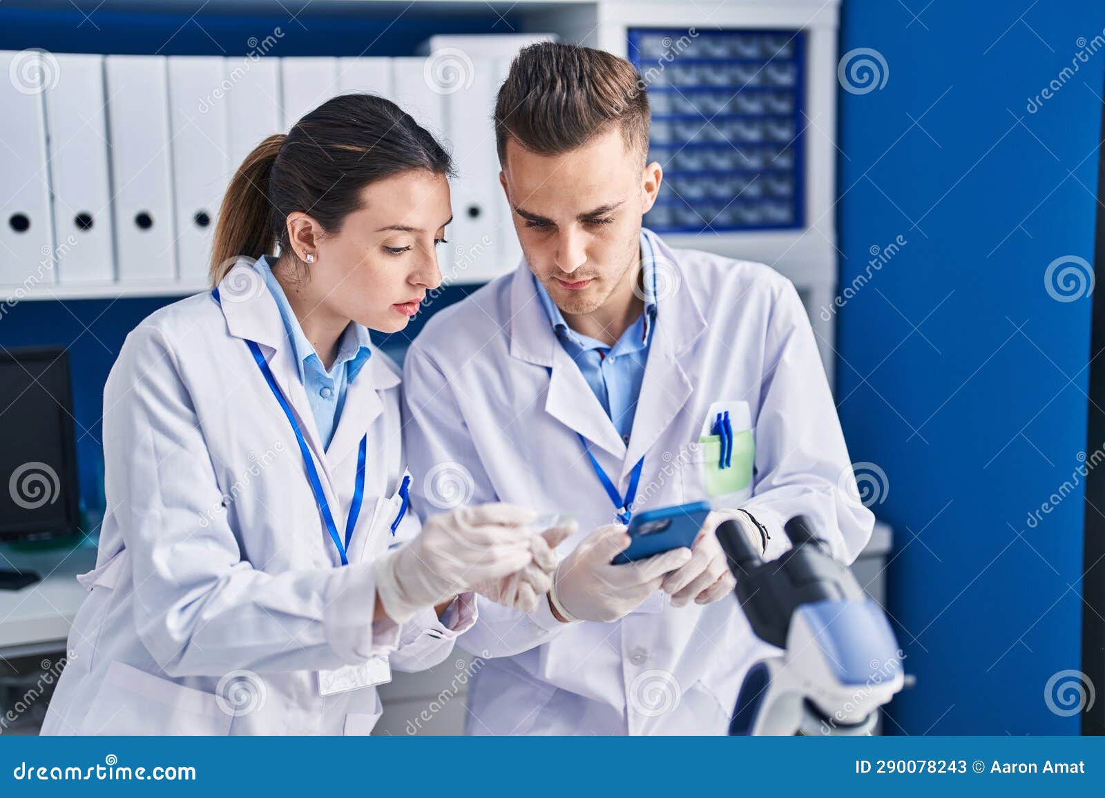 Man and Woman Scientists Using Smartphone Looking Sample at Laboratory ...