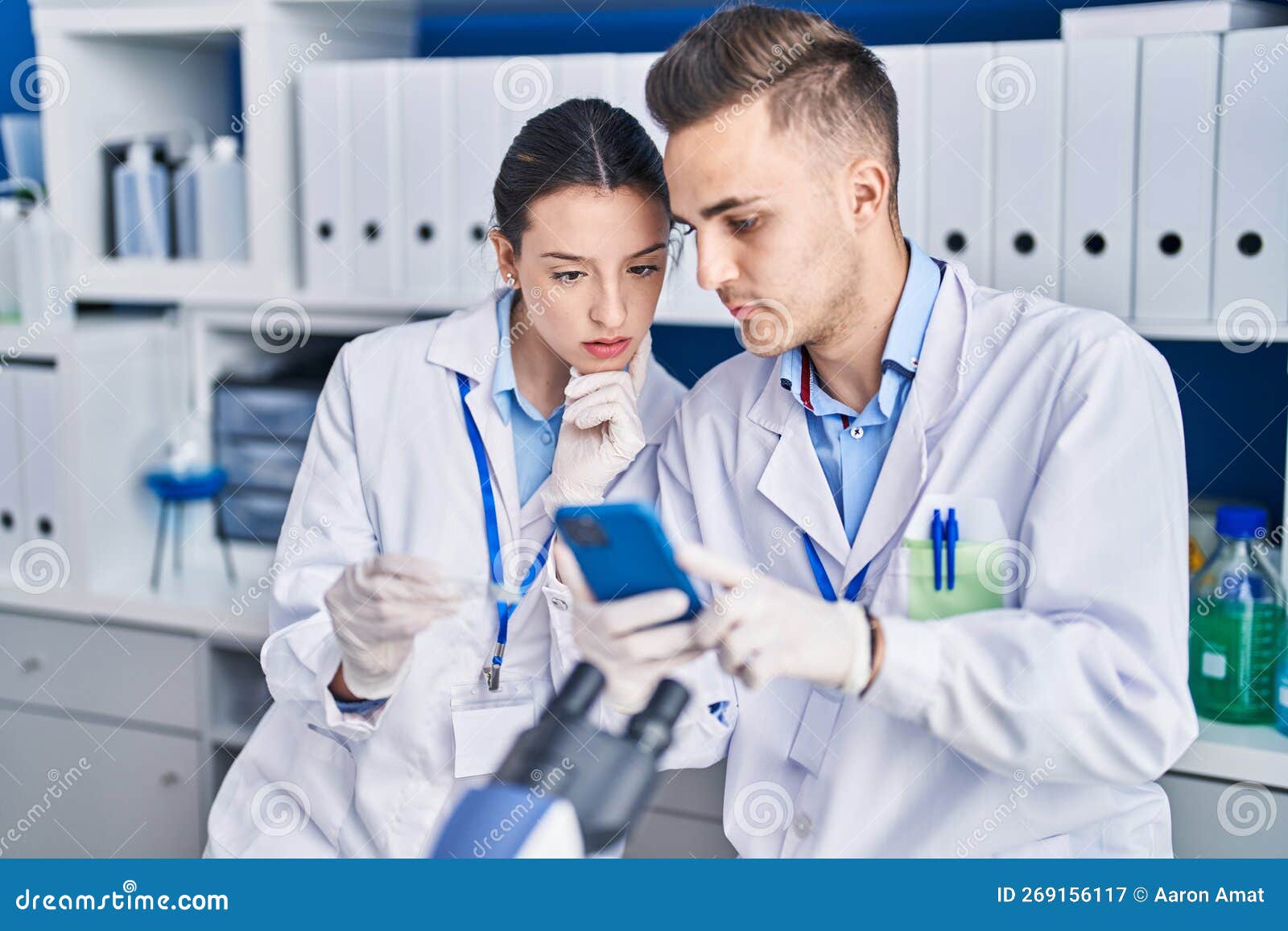 Man and Woman Scientists Using Smartphone Looking Sample at Laboratory ...