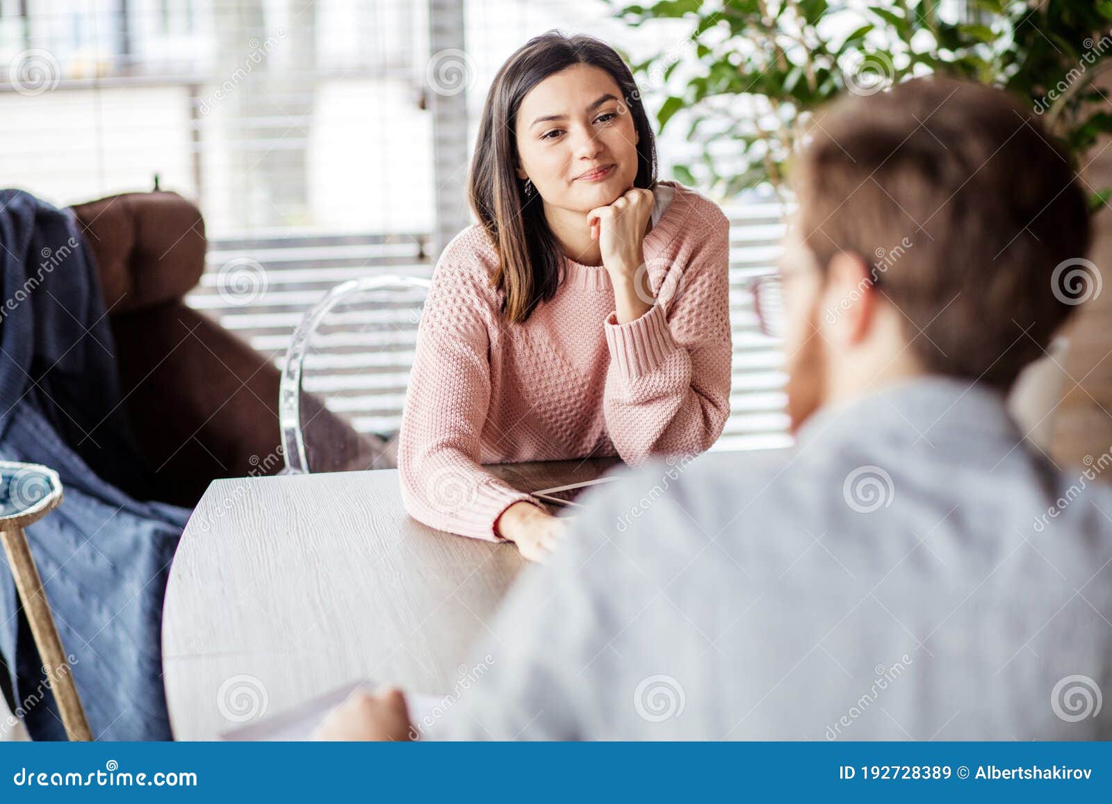 A Man And A Woman Are Sitting At A Table Opposite Each Other Stock
