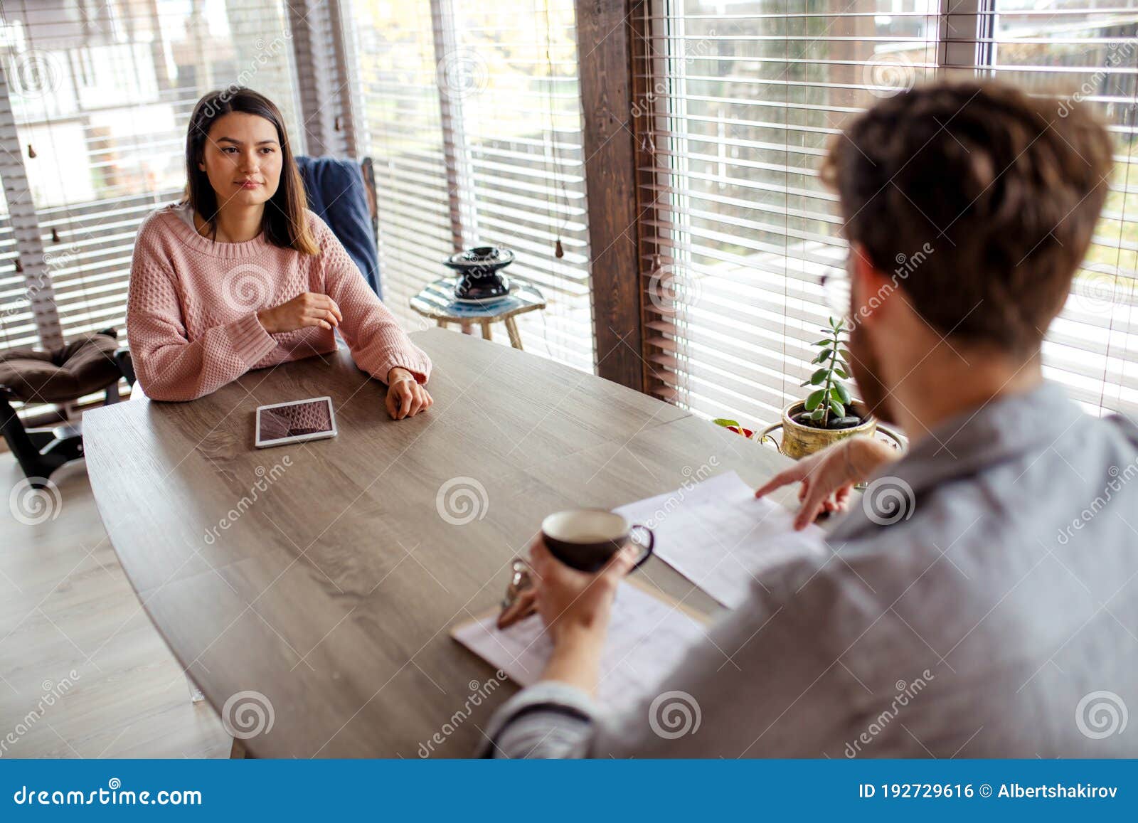 A Man And A Woman Are Sitting At A Table Opposite Each Other Stock