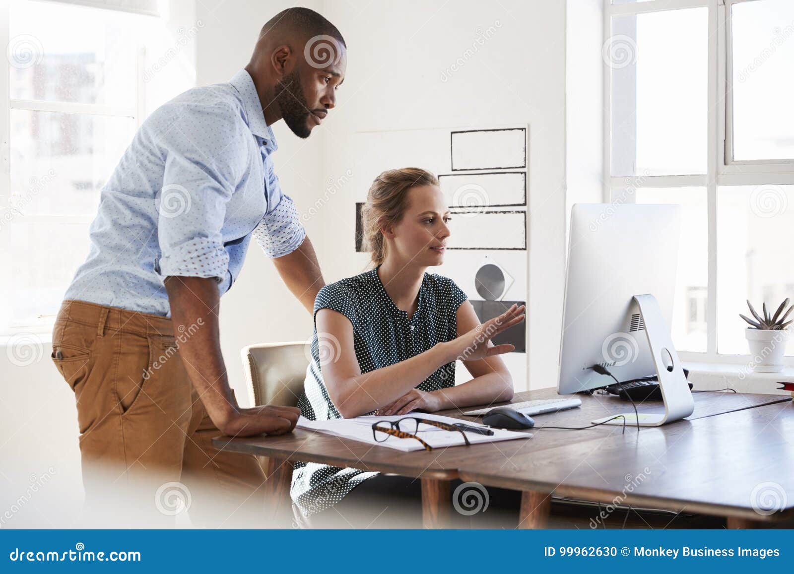 Man and Woman Talk in an Office Looking at Computer Screen Stock Photo ...