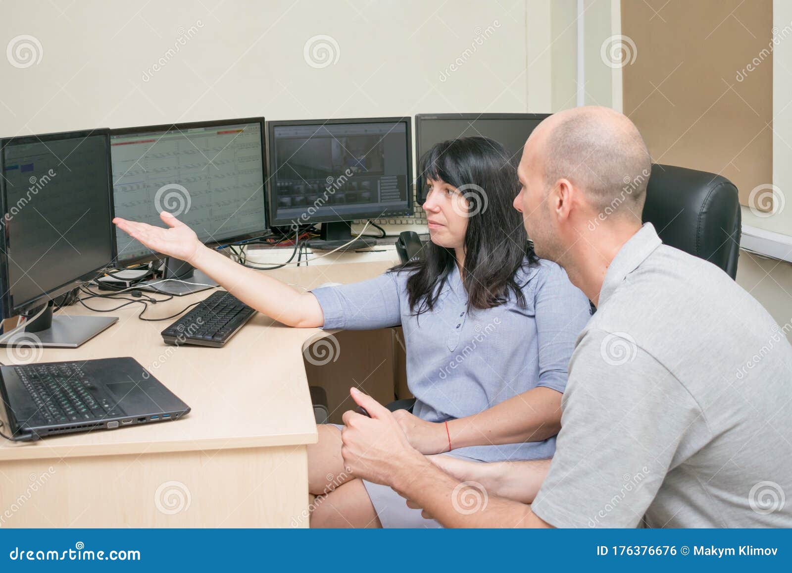 A Man and a Woman are Talking in Front of the Screens of Computer ...