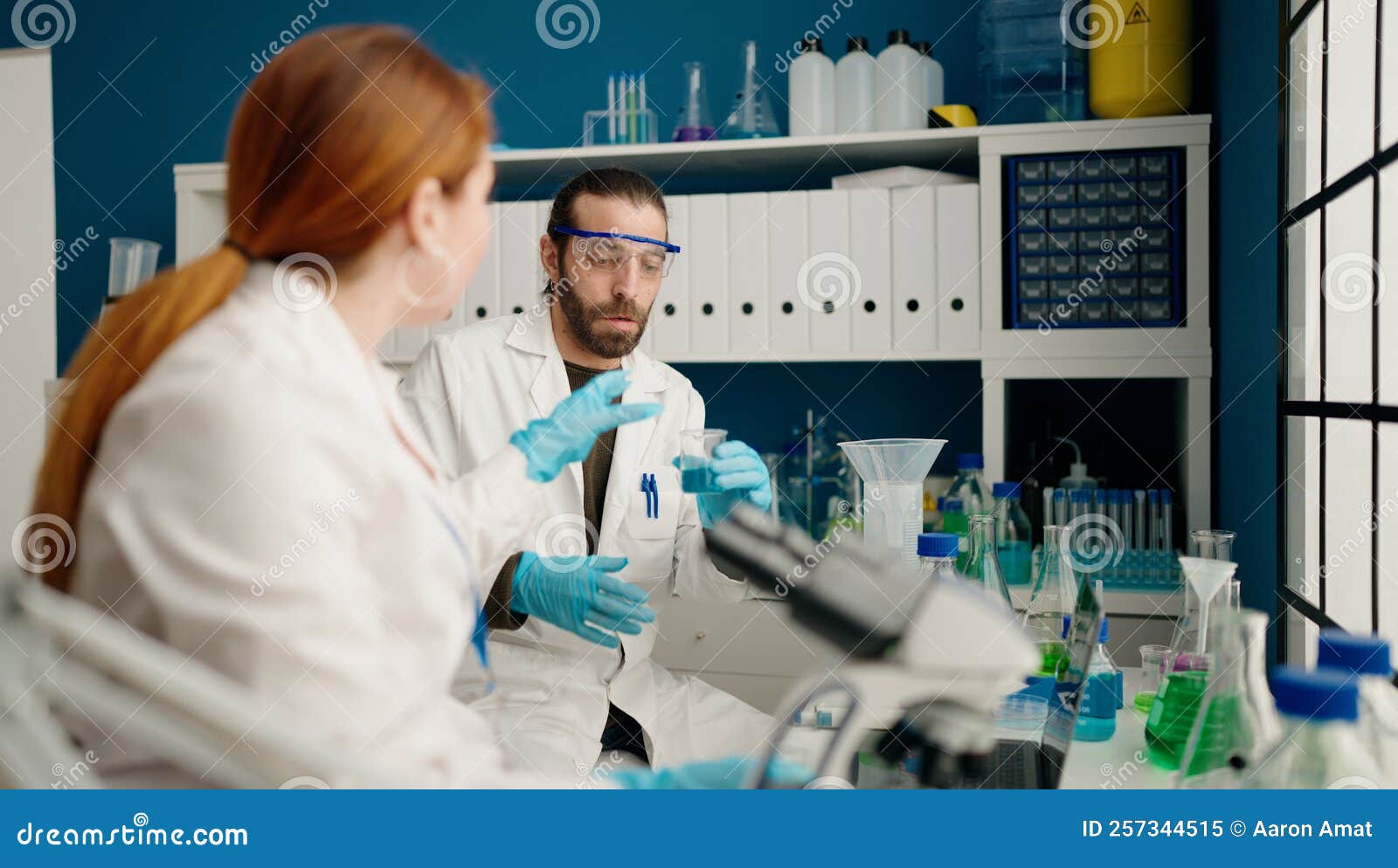 Man and Woman Wearing Sciencist Uniform Using Microscope at Laboratory ...