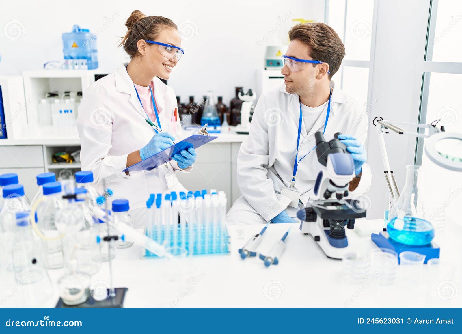 Man and Woman Wearing Scientist Uniform Using Microscope Write on ...
