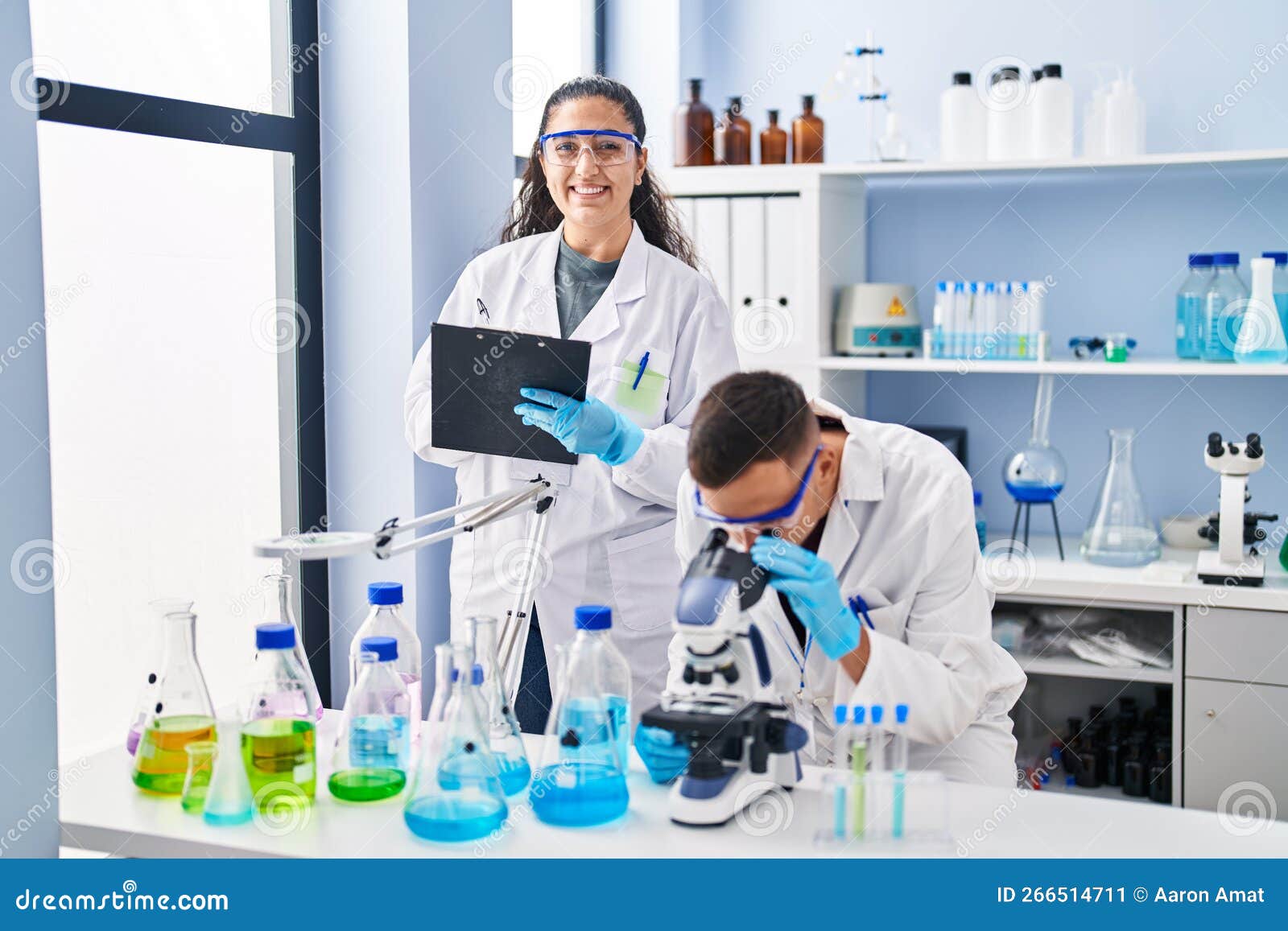 Man and Woman Wearing Scientist Uniform Using Microscope Write on ...