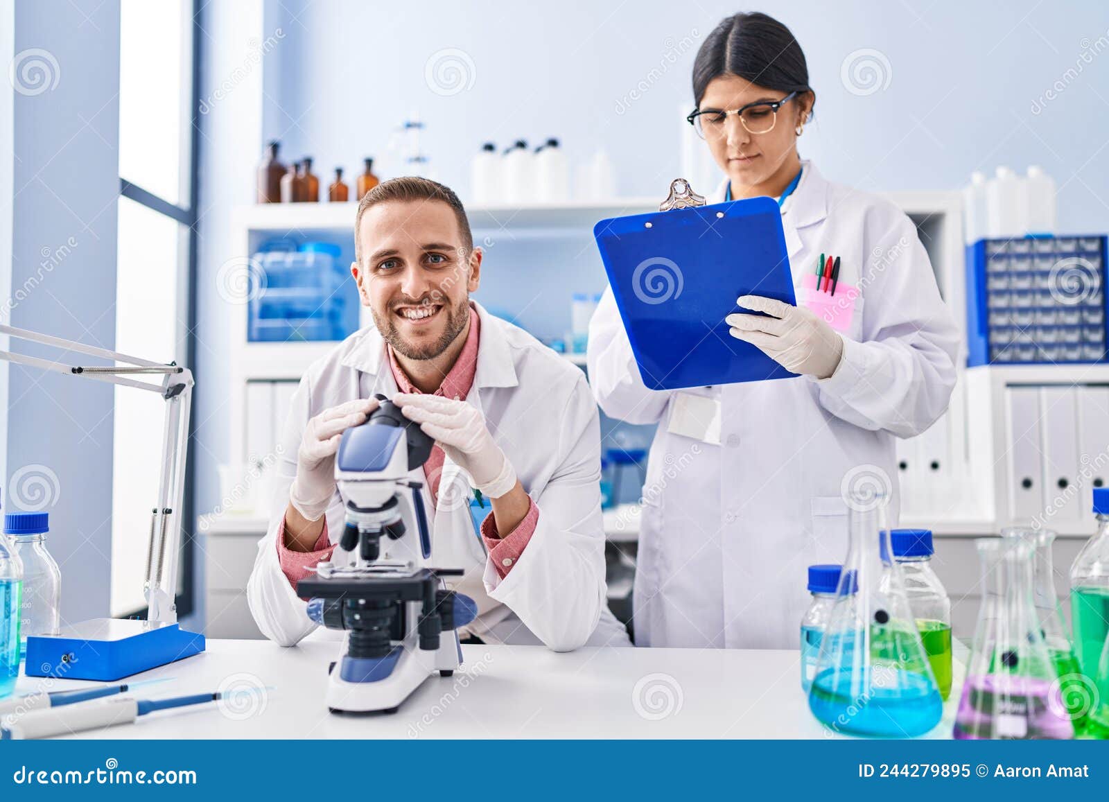Man and Woman Wearing Scientists Uniform Using Microscope at Laboratory ...