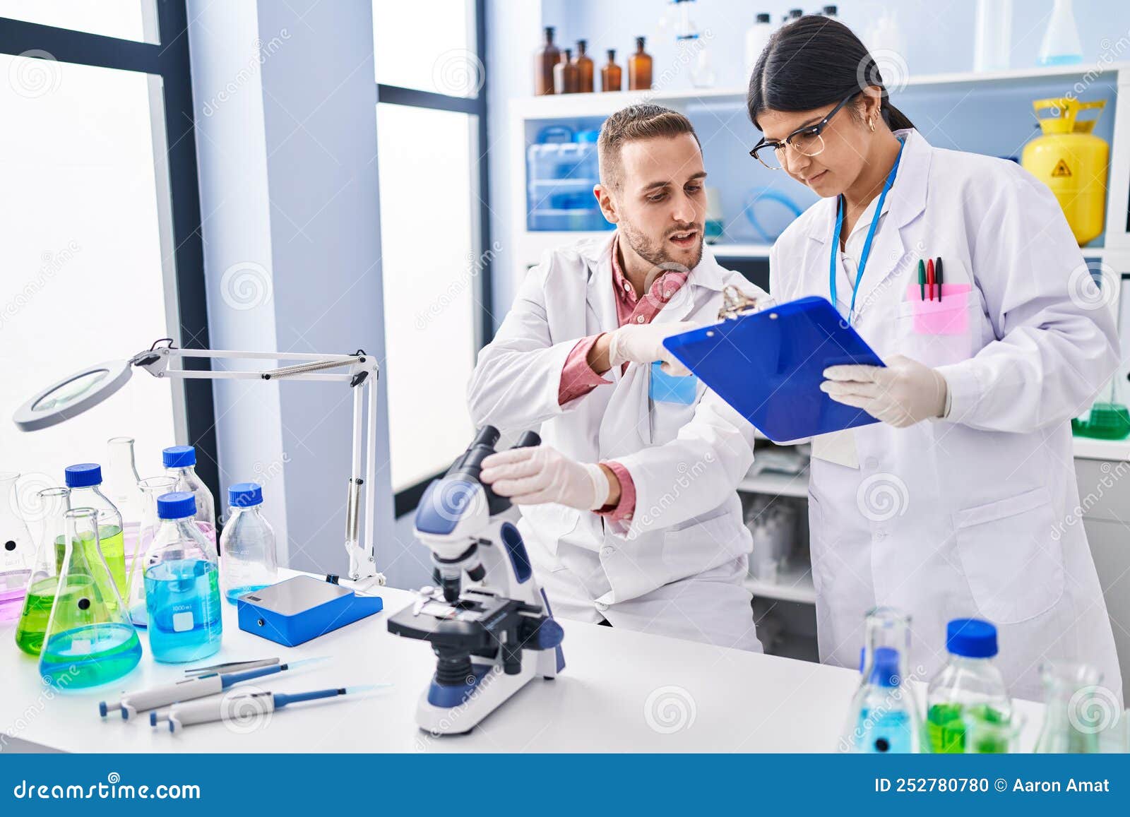 Man and Woman Wearing Scientists Uniform Using Microscope at Laboratory ...