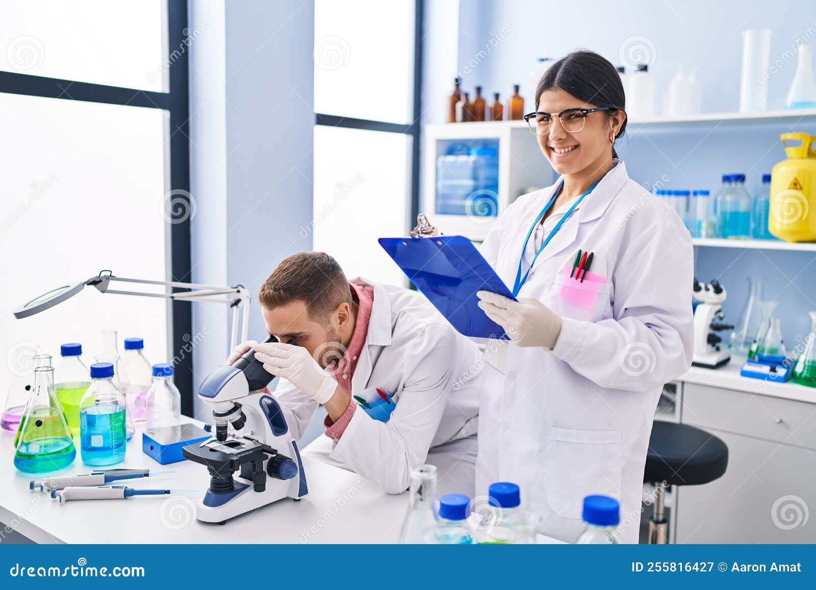 Man and Woman Wearing Scientists Uniform Using Microscope at Laboratory ...