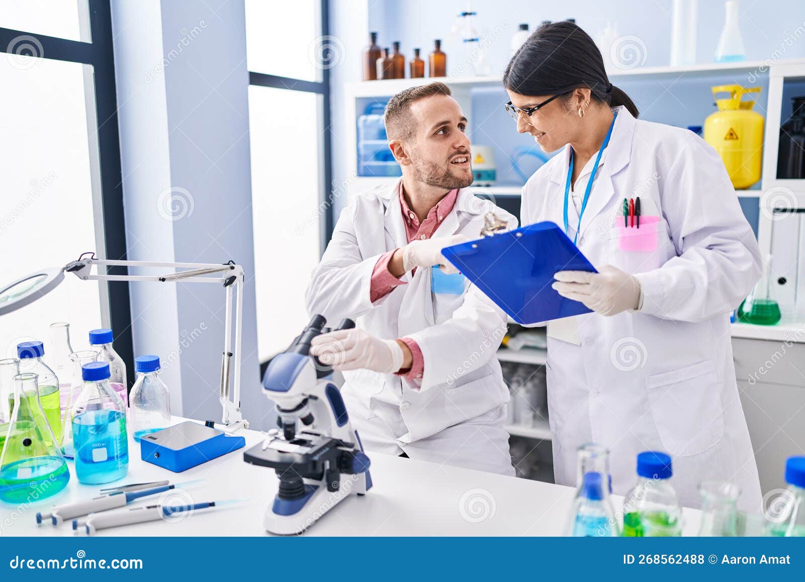 Man and Woman Wearing Scientists Uniform Using Microscope at Laboratory ...