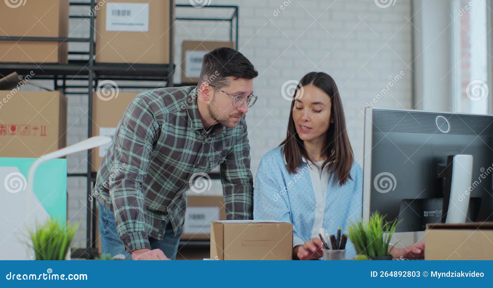 A Man and a Woman Work in a Warehouse. Young Woman Using Computer, Man ...