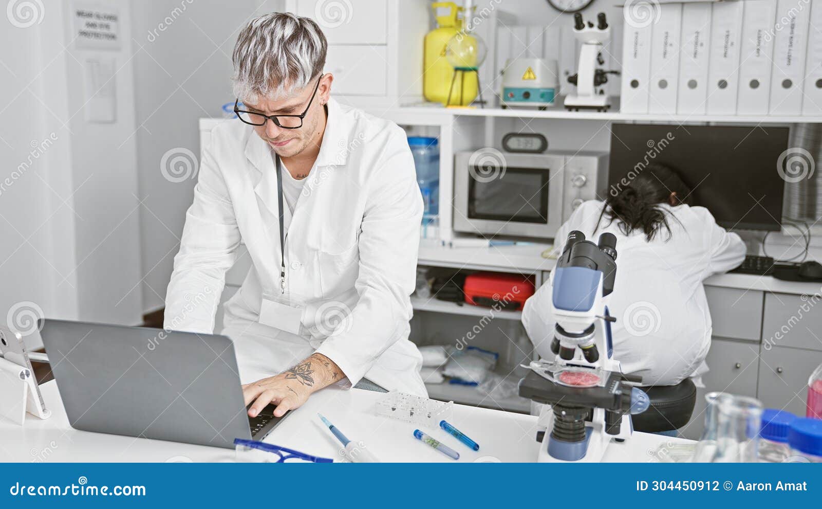 A Man and Woman Working As Coworkers in a Laboratory, with Him Using a ...