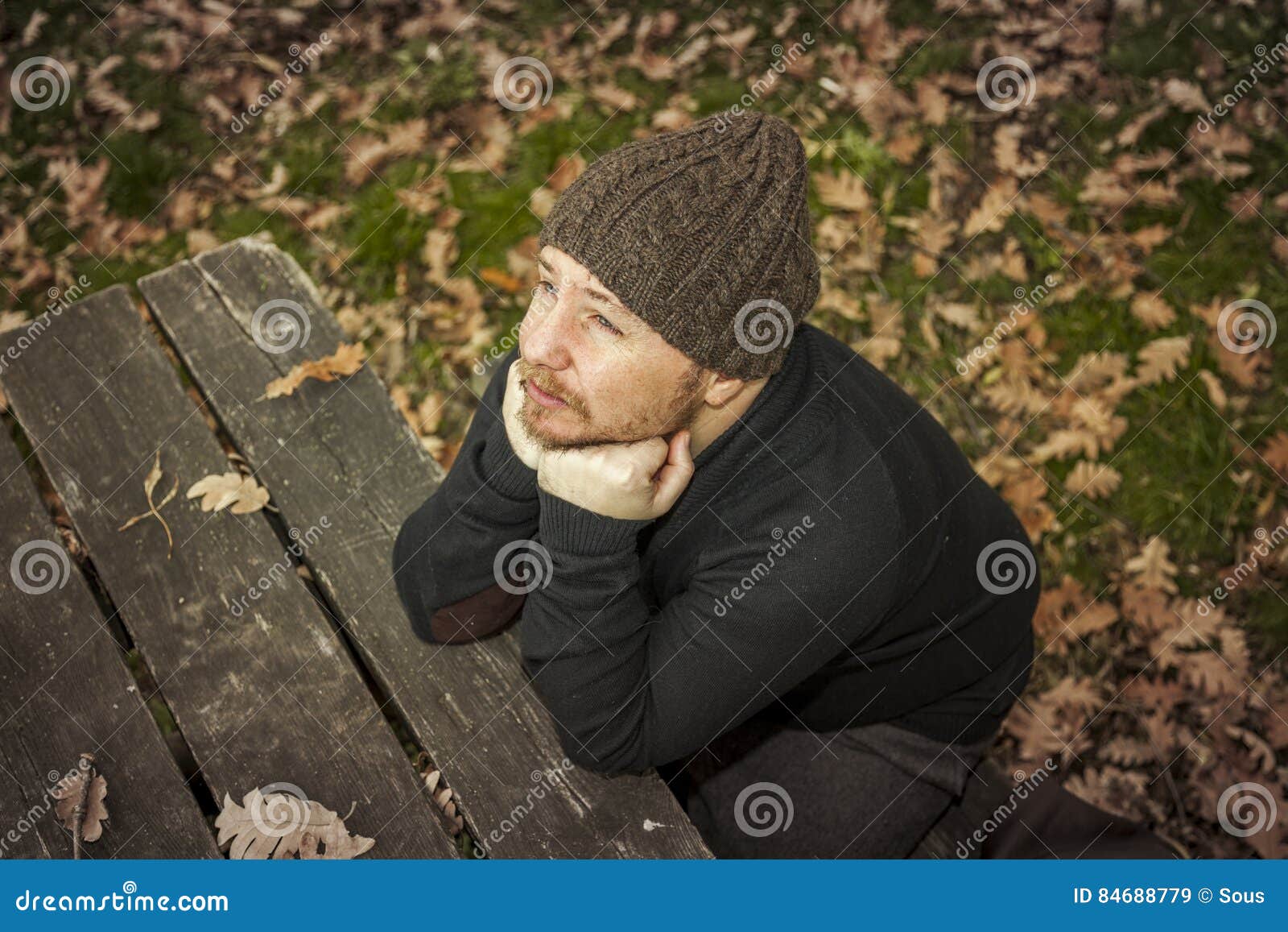 Man with Wool Hat Sitting on the Bench in the Park Looking at Sk Stock ...