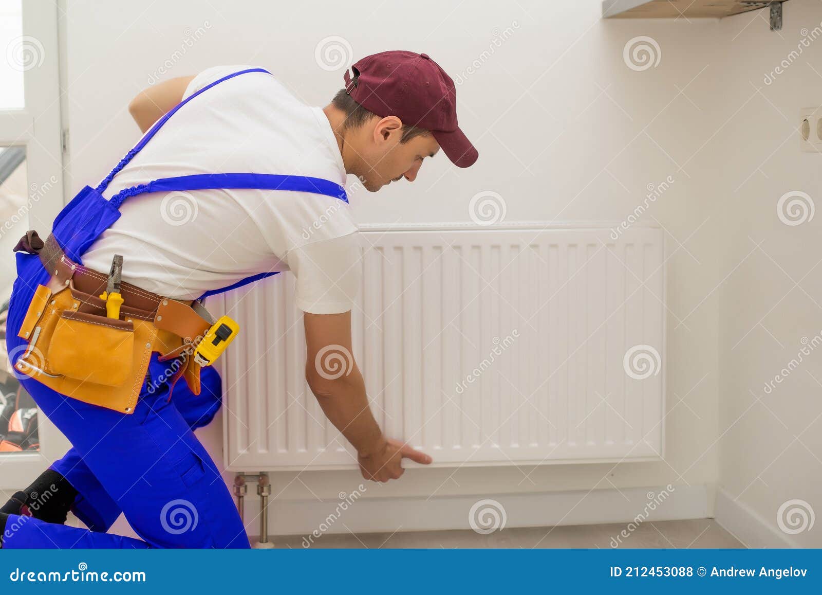 Man in Work Overalls Using Wrench while Installing Heating Radiator in ...