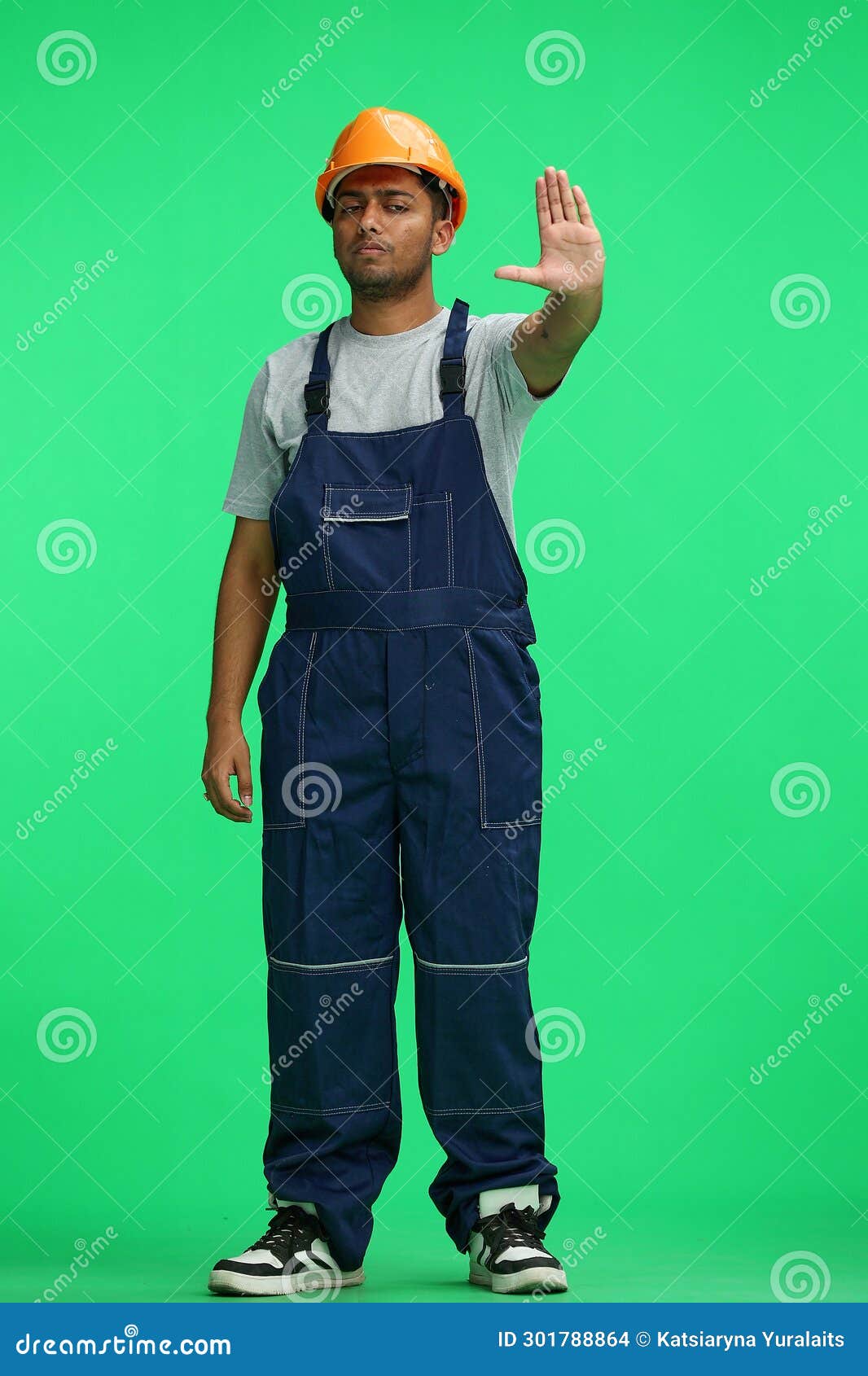 A Man in a Work Uniform on Green Background Shows a Stop Sign Stock ...