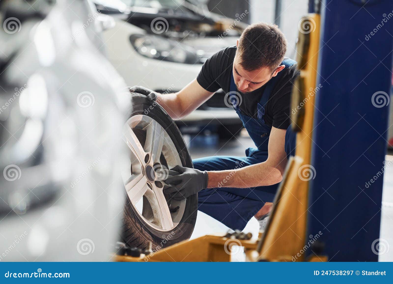 Man in Work Uniform Sitting and Changing Car Wheel Indoors. Conception ...