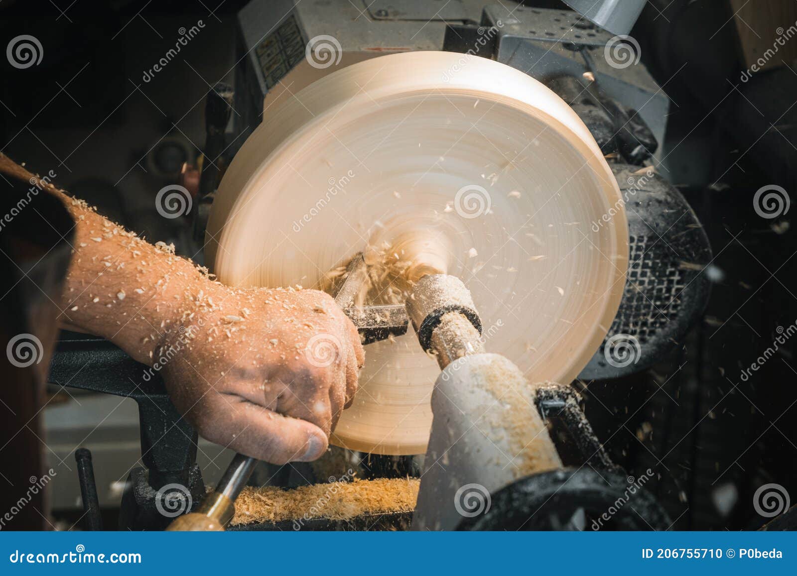 A Man in a Working Apron Works on a Wood Turning Lathe Stock Photo ...