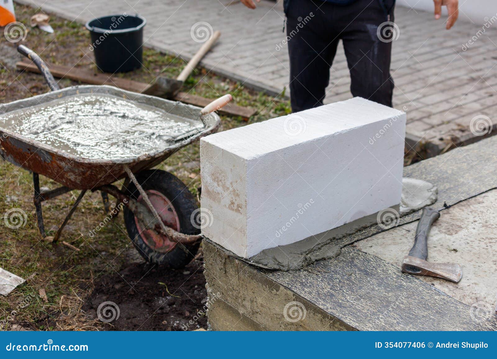 A Man is Working on a Brick Wall with a Wheelbarrow and a Hammer Stock ...