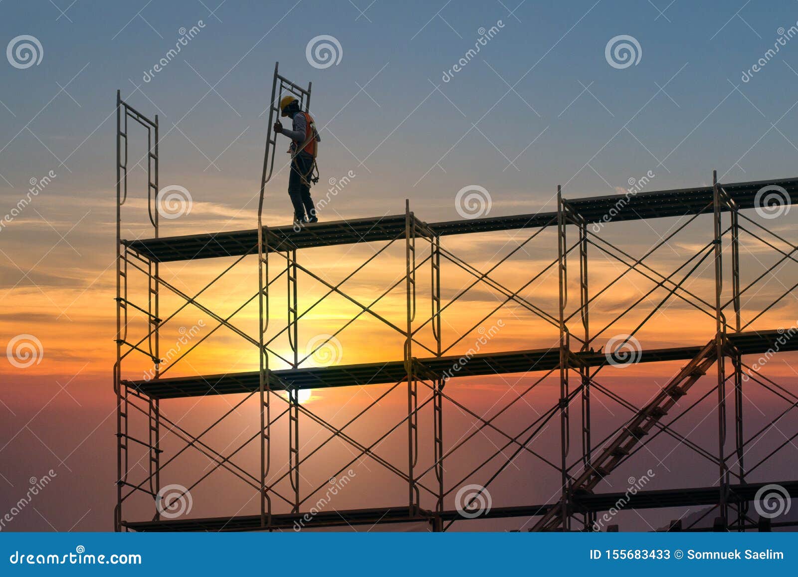 Man Working on Construction Site with Scaffold and Building with Sunset ...