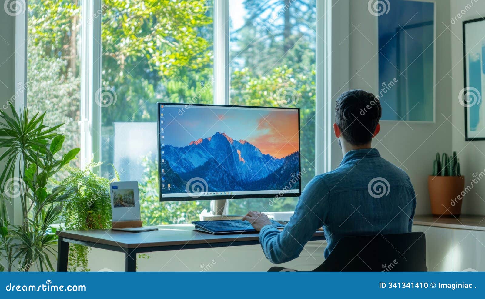 Man Working at a Desk with a Mountain Landscape Desktop Background ...