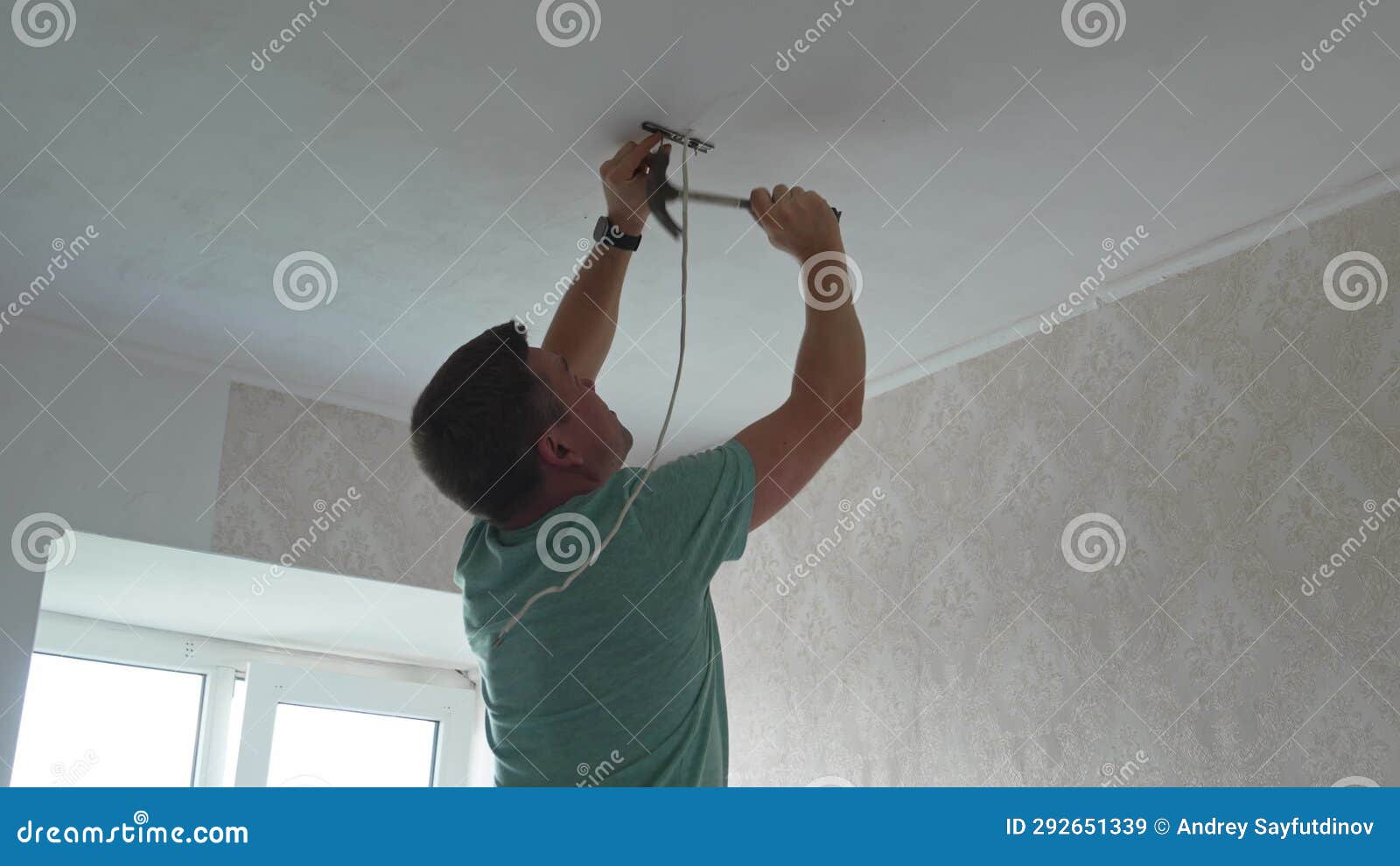 A Man is Working on the Installation of a Ceiling Luminaire on the ...
