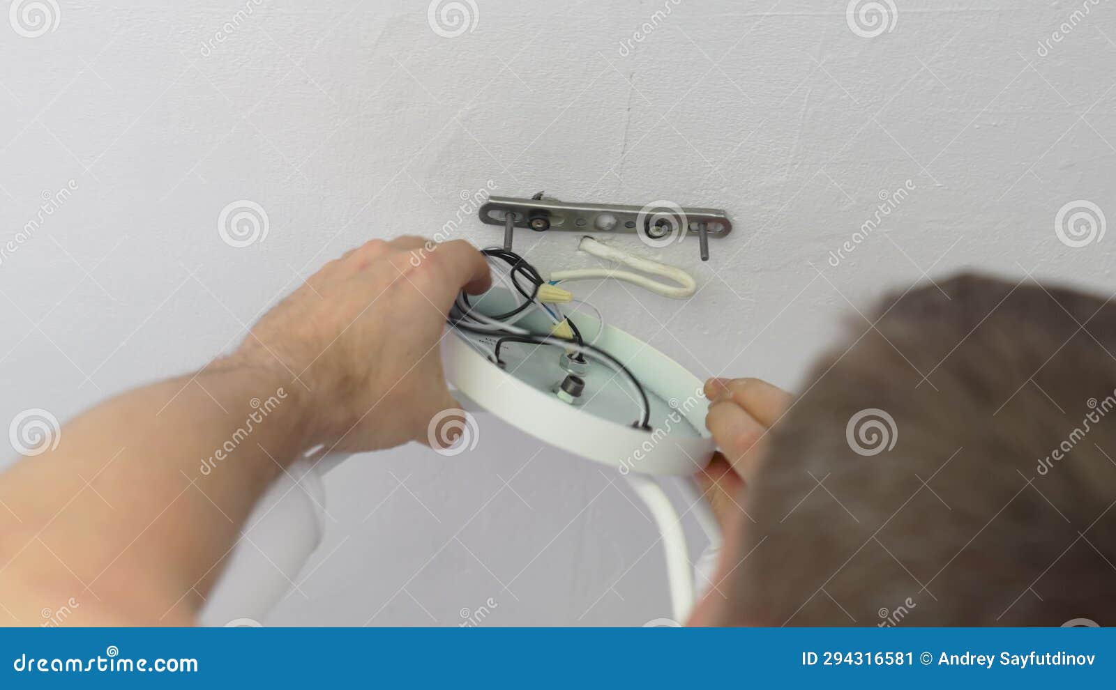 A Man is Working on the Installation of a Ceiling Luminaire on the ...