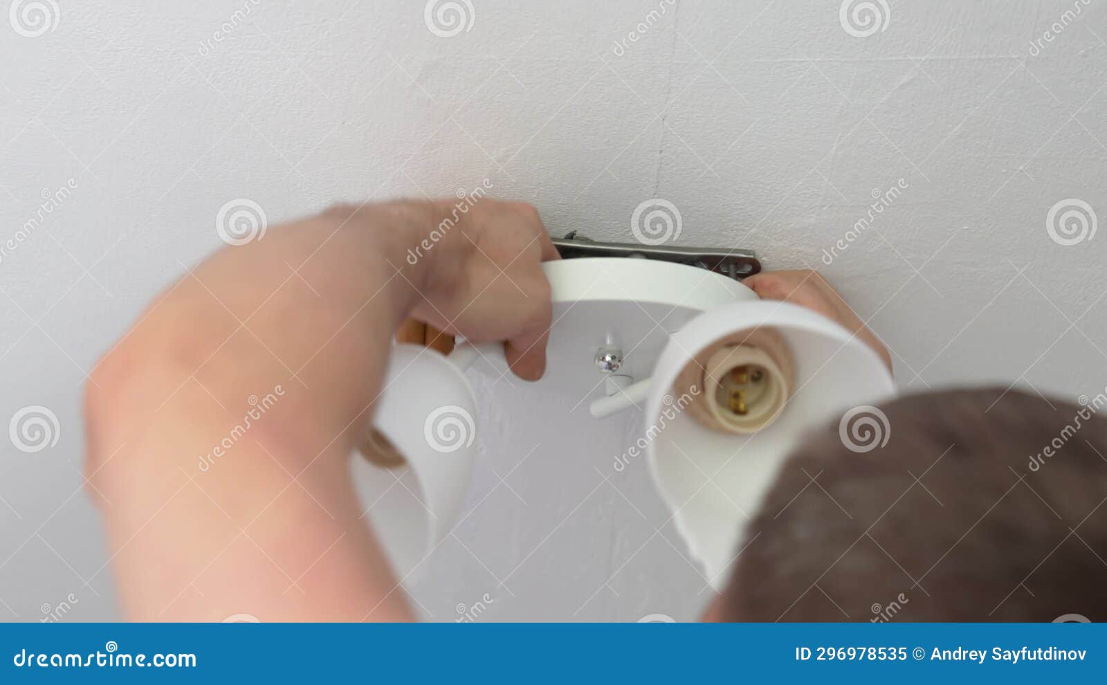 A Man is Working on the Installation of a Ceiling Luminaire on the ...