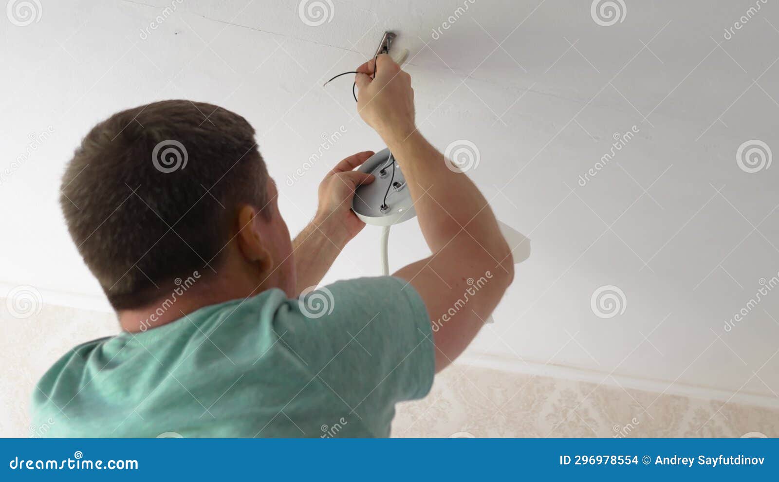 A Man is Working on the Installation of a Ceiling Luminaire on the ...