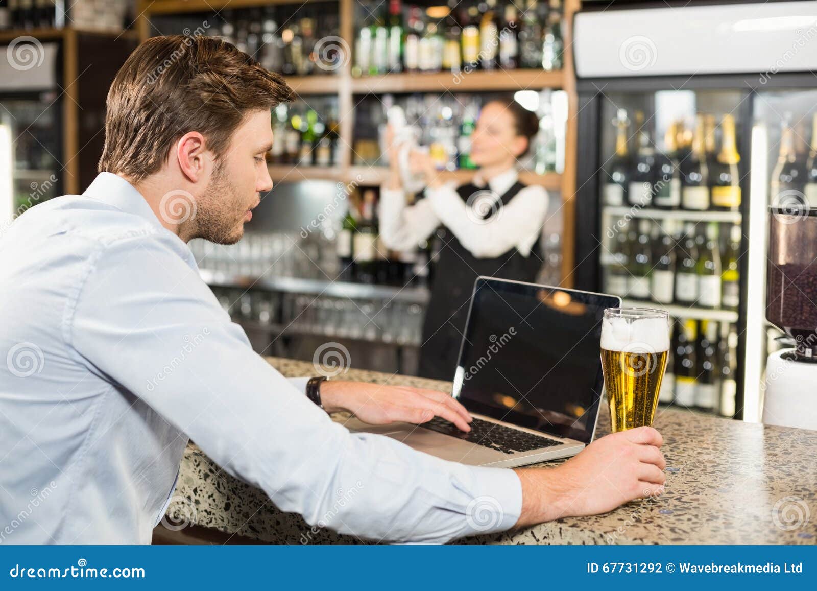 Man Working on Laptop with Beer in Hand Stock Photo - Image of counter ...