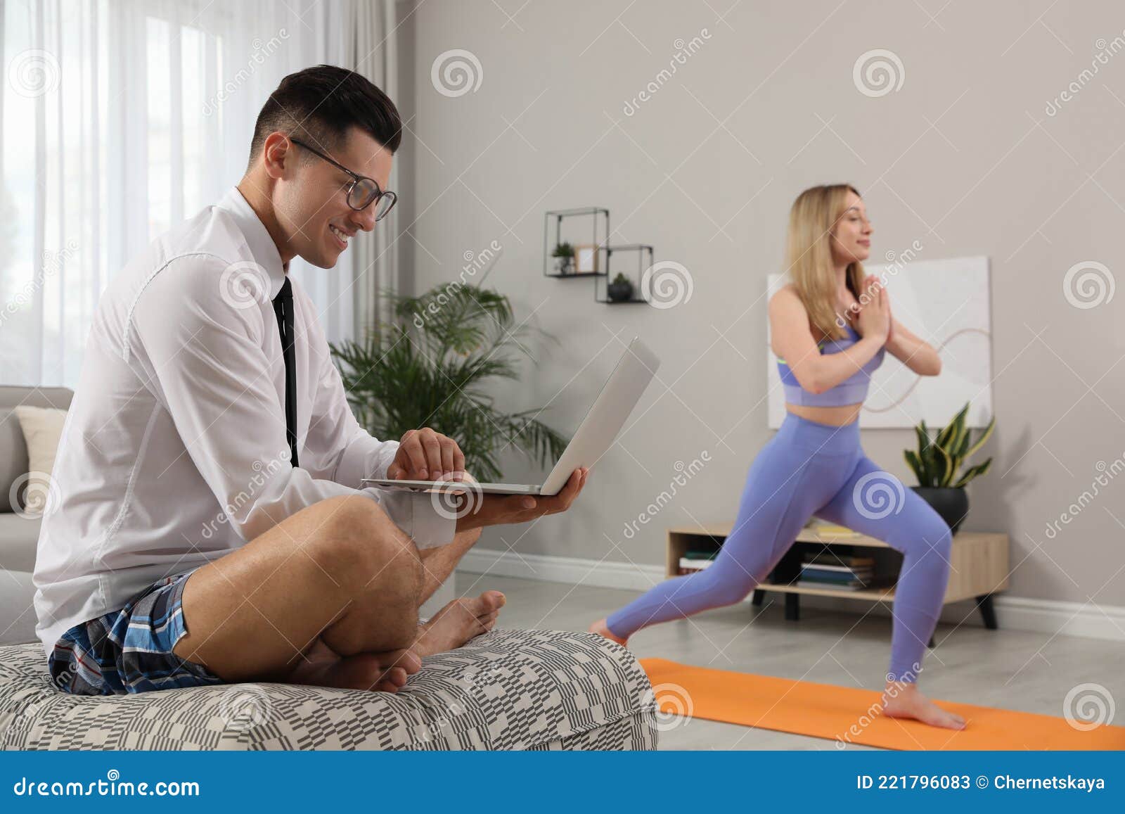 Man Working on Laptop while Wife Practicing Yoga in Living Room. Stay ... Man Working on Laptop while Wife Practicing Yoga in Living Room. Stay ...