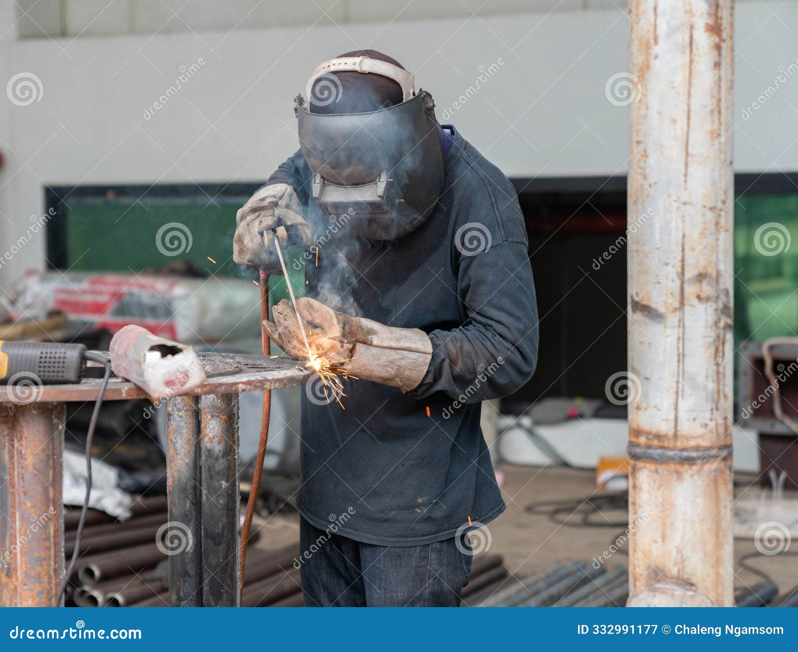 Man is Working at Metal Factory, he is Welding a Edge of Boiler Frame ...